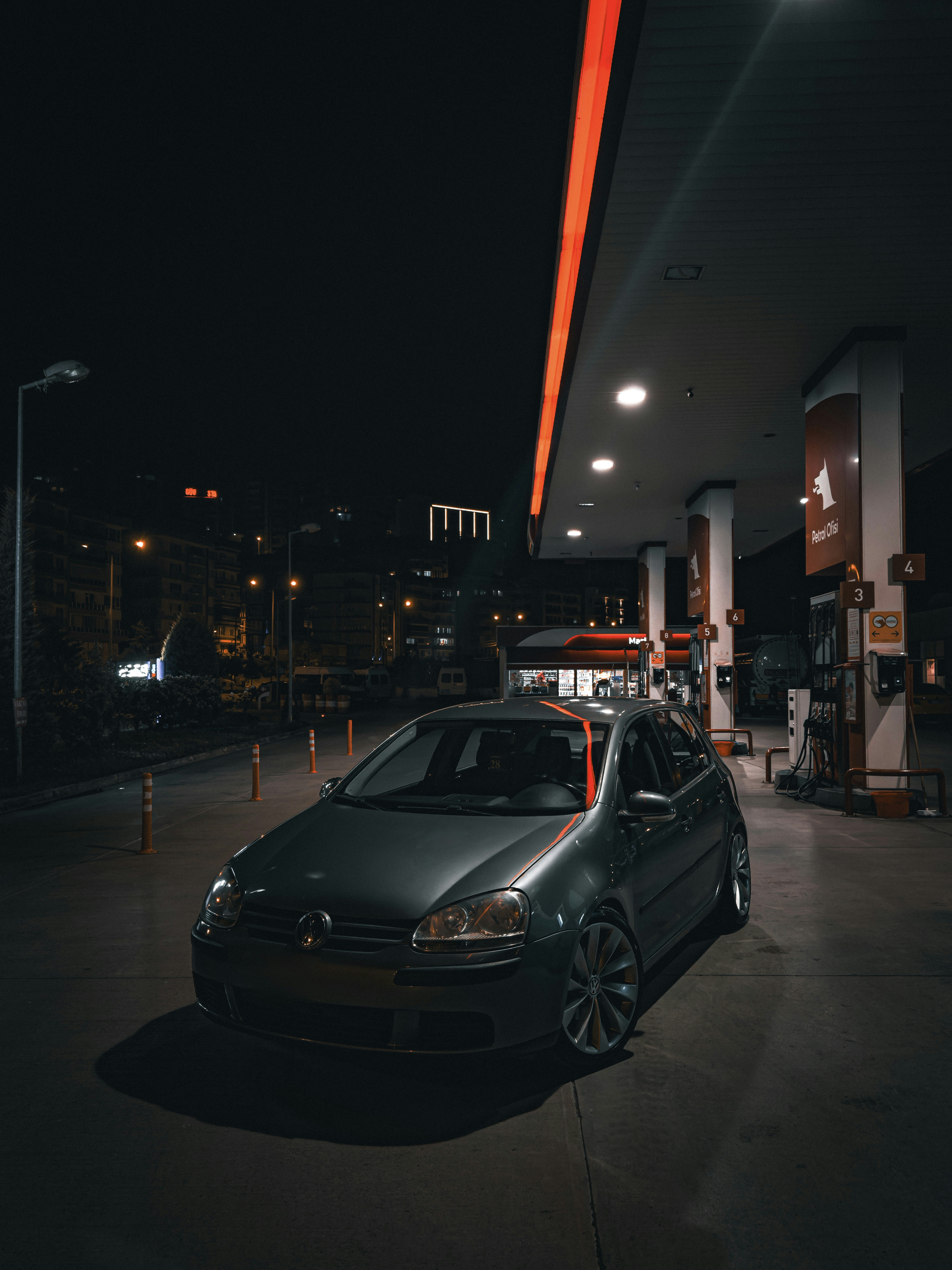 Urban Night Reflections: A Car's Solitude at the Pump