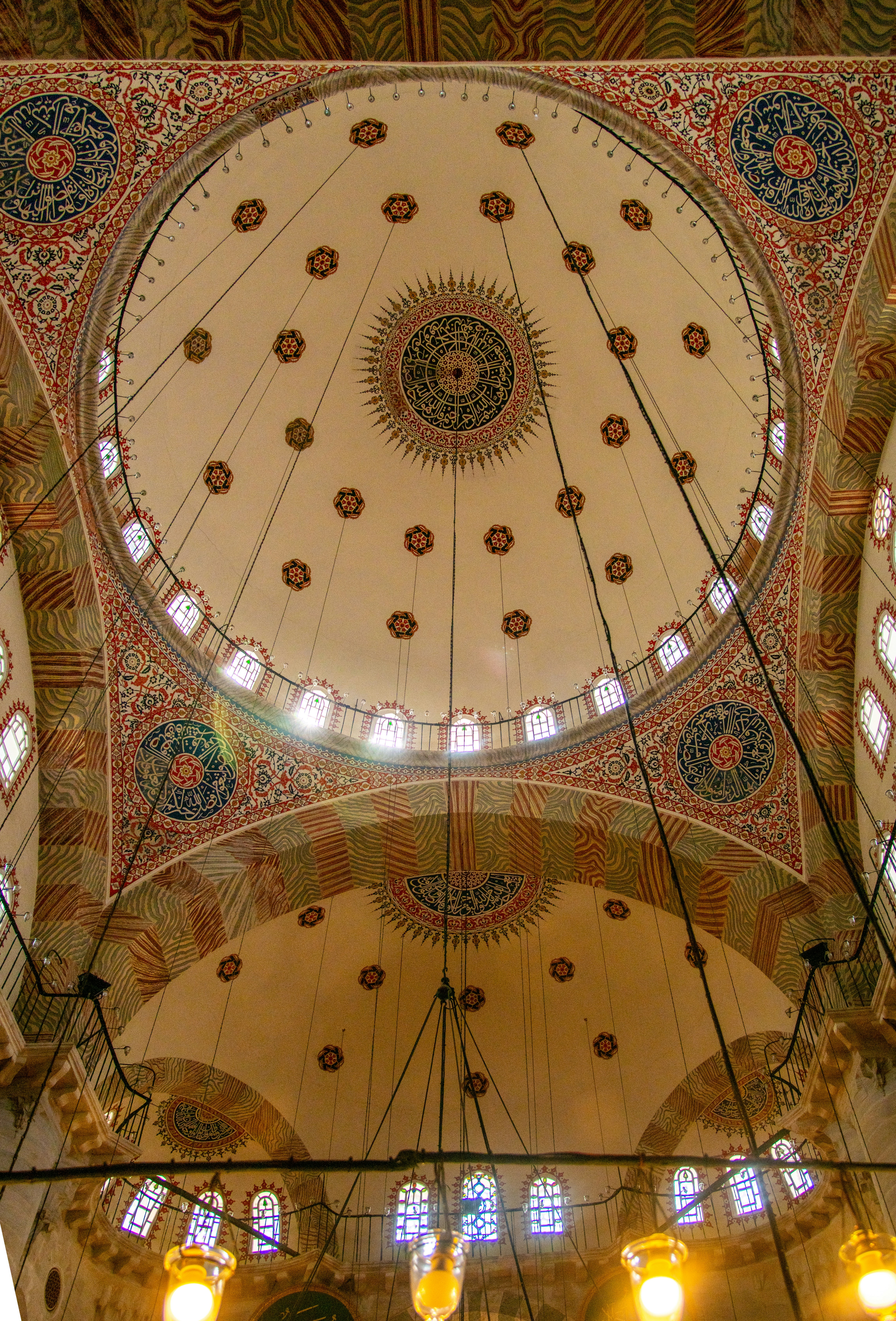 A mosque's ornate ceiling and dome are shown.