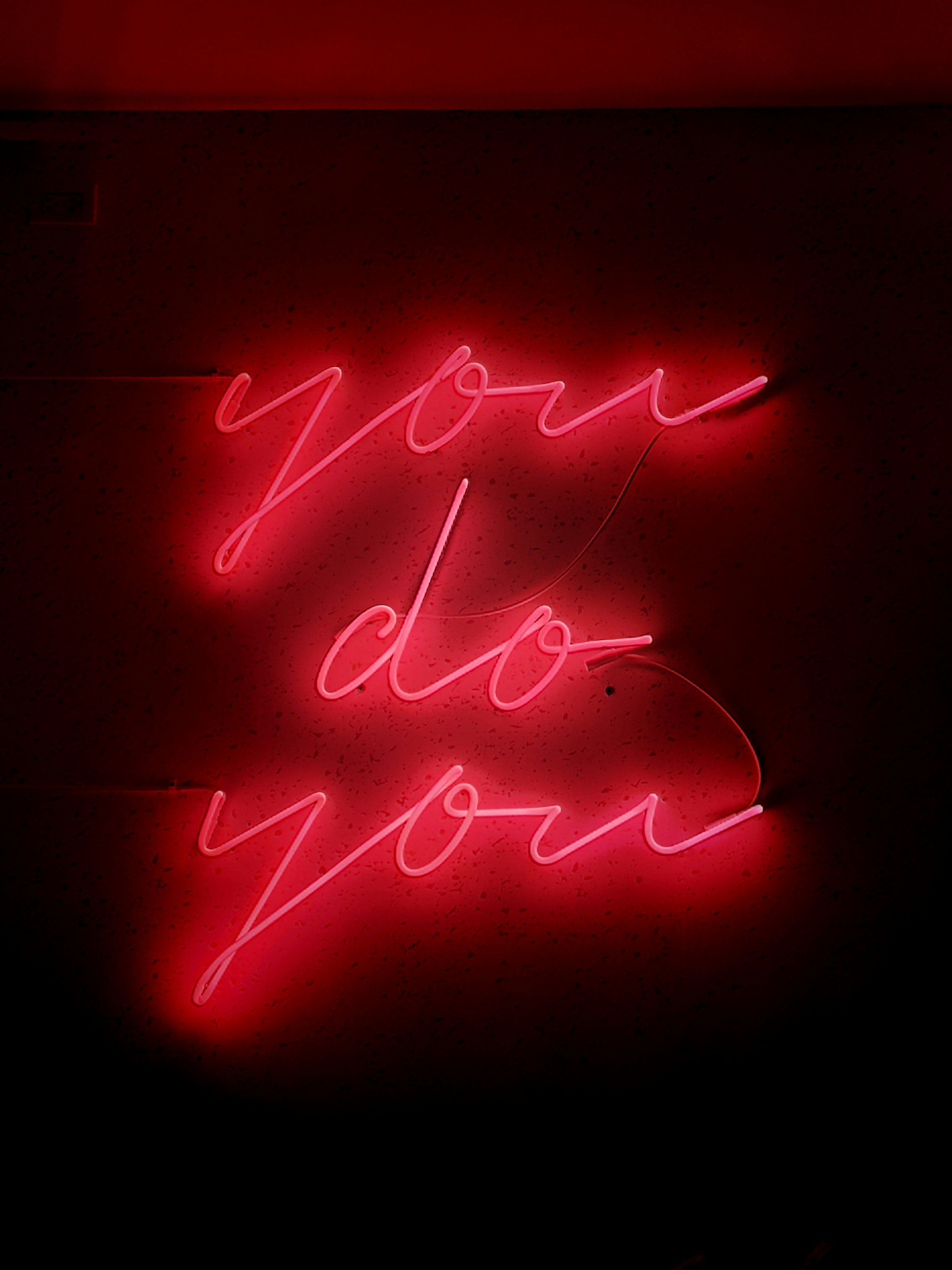 Neon sign displaying the phrase 'you do you' in vibrant pink against a dark background.