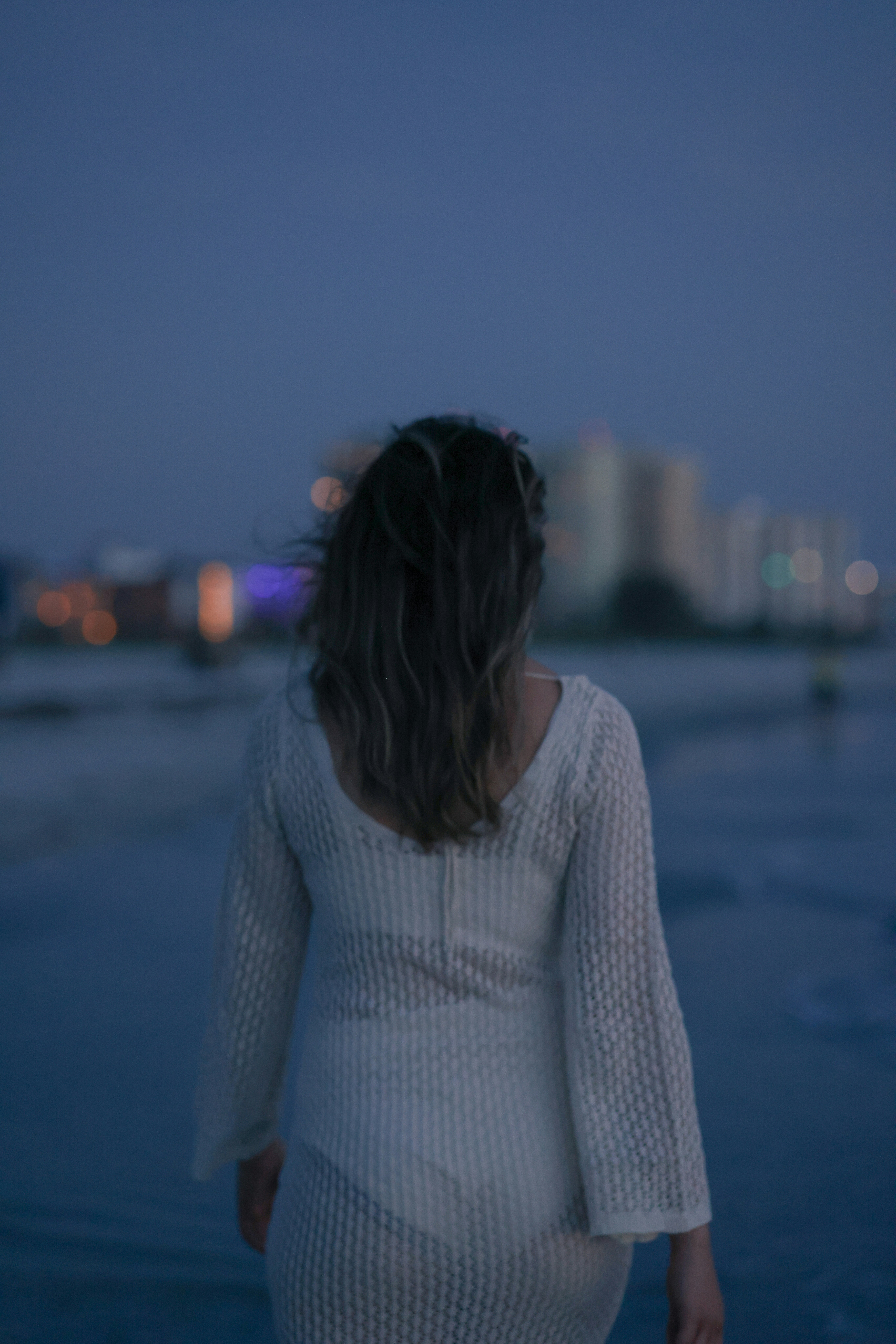 Woman walks into the ocean at dusk.