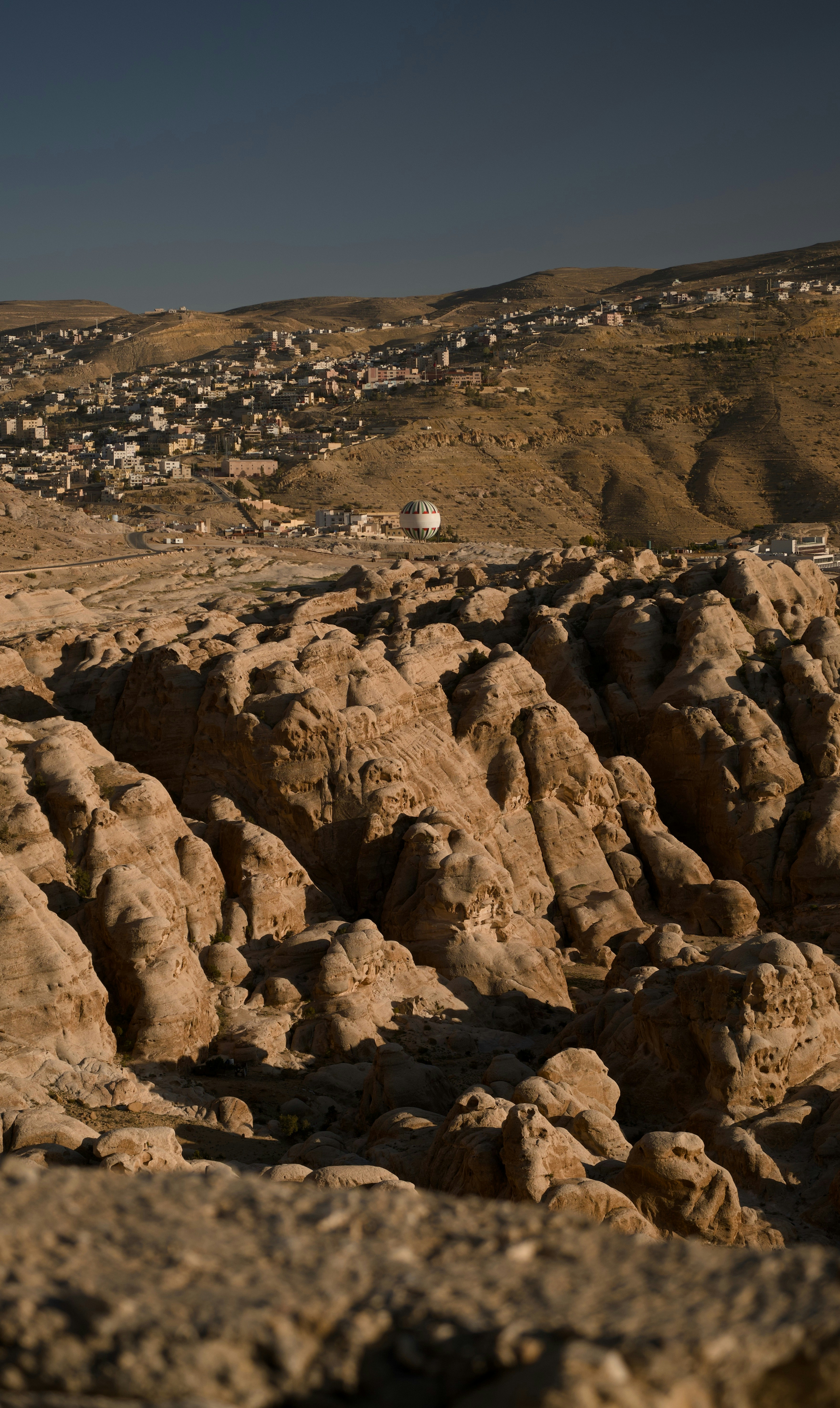 Rocky landscape with a town and hot air balloon.