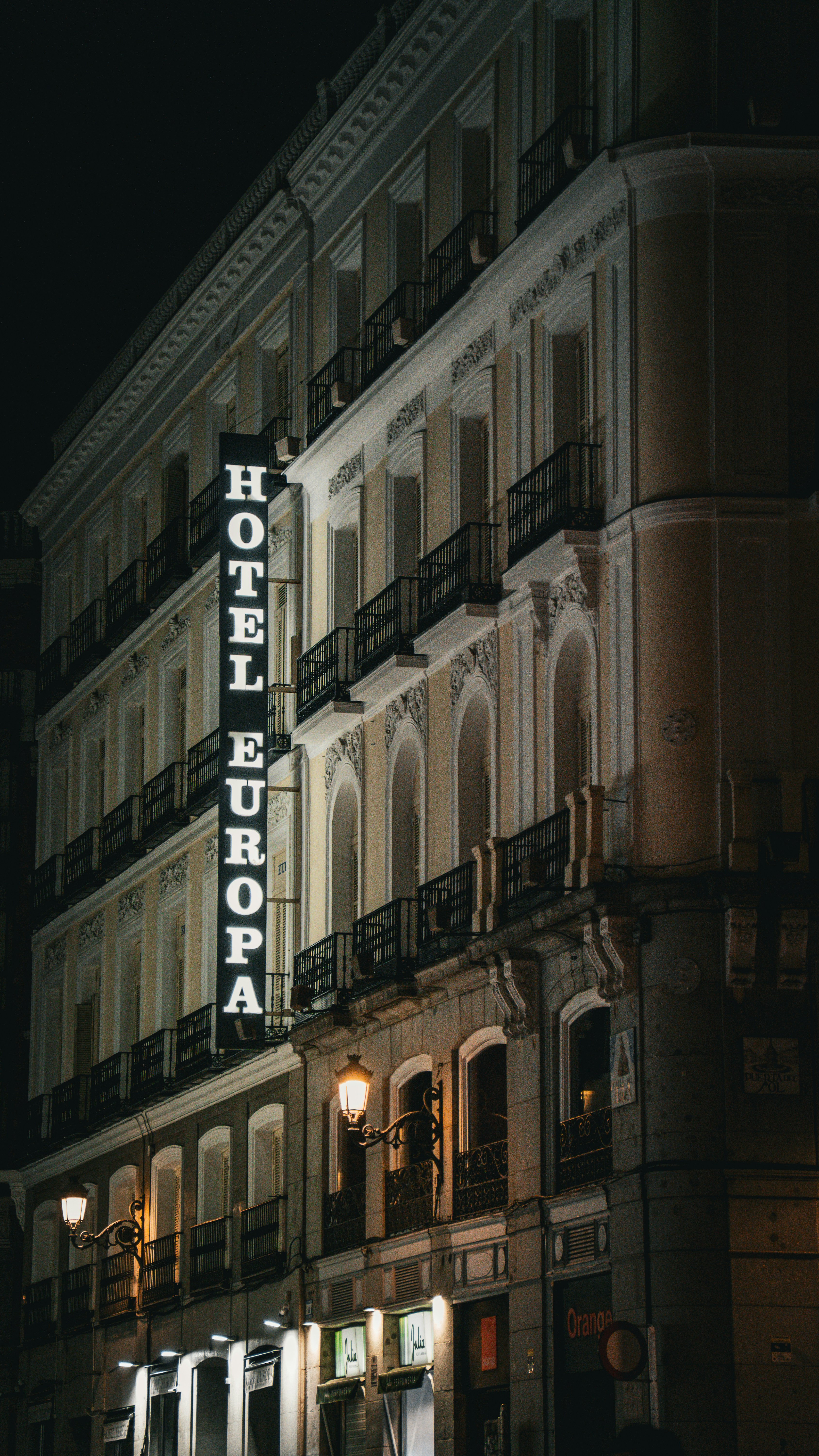 Neoclassical hotel facade illuminated at night, showcasing the prominent 'Hotel Europa' sign and decorative architectural details.