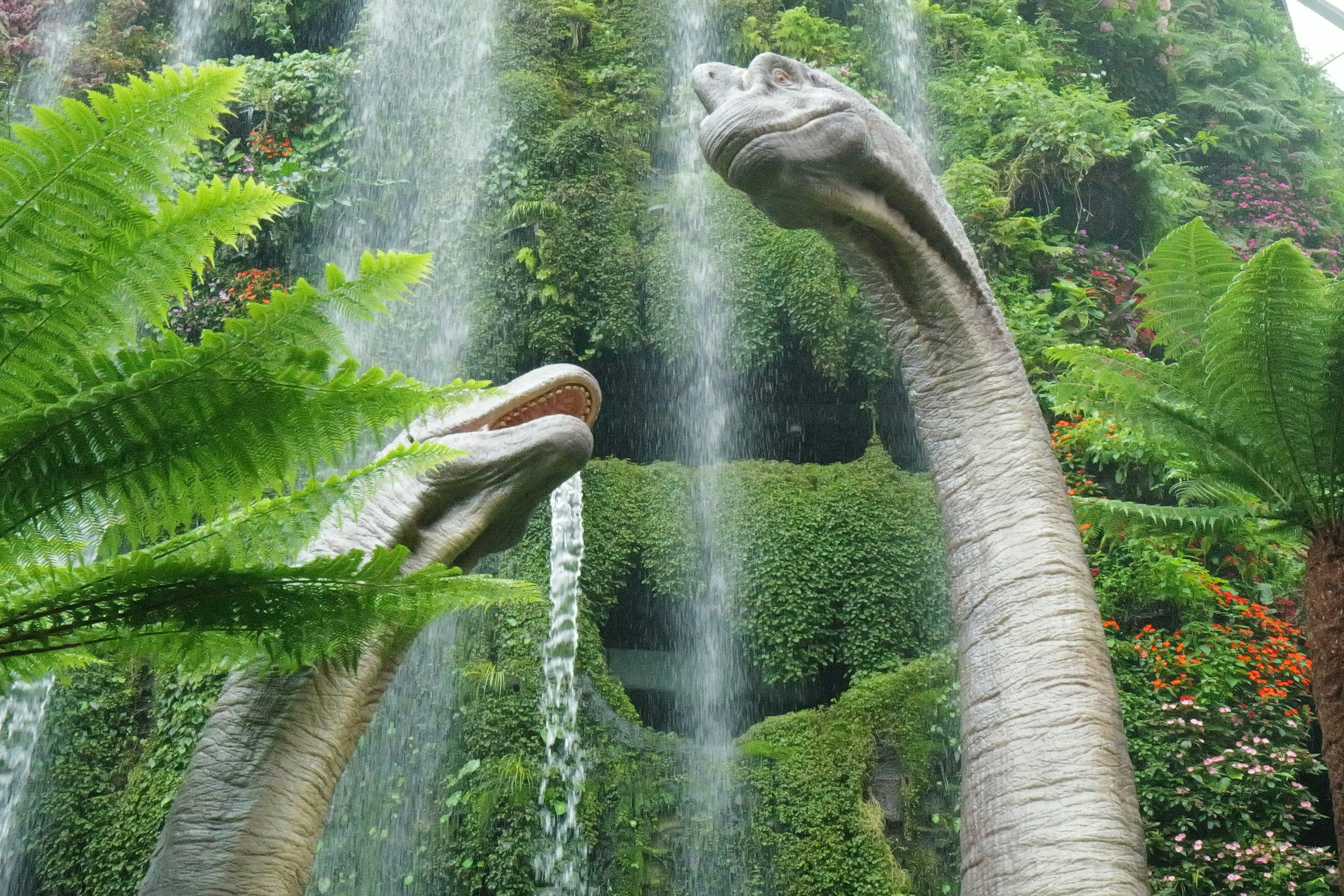 Dinosaurs stand near a waterfall in lush foliage. photo – Free Forest ...