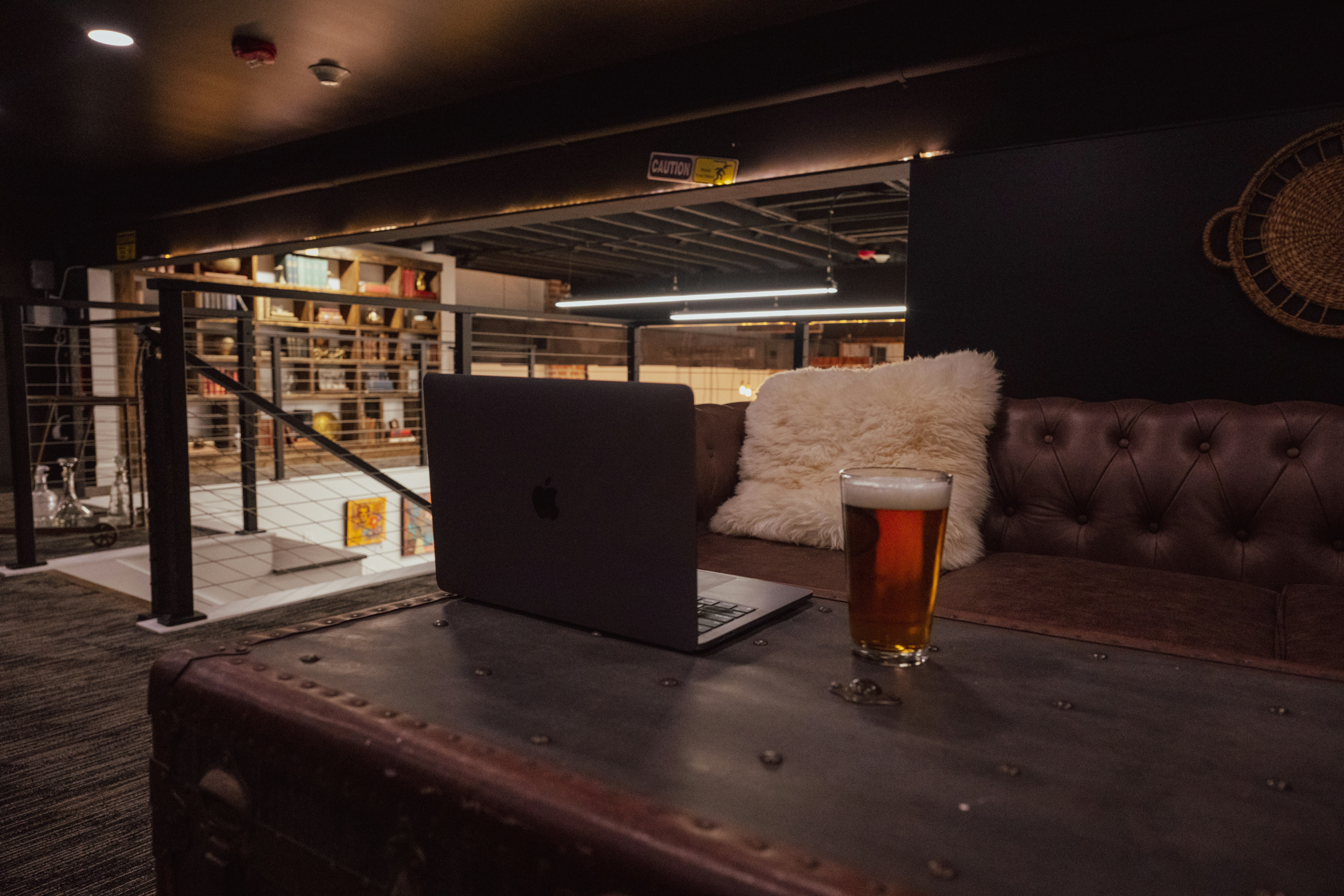 A laptop and beer sit on a vintage trunk.