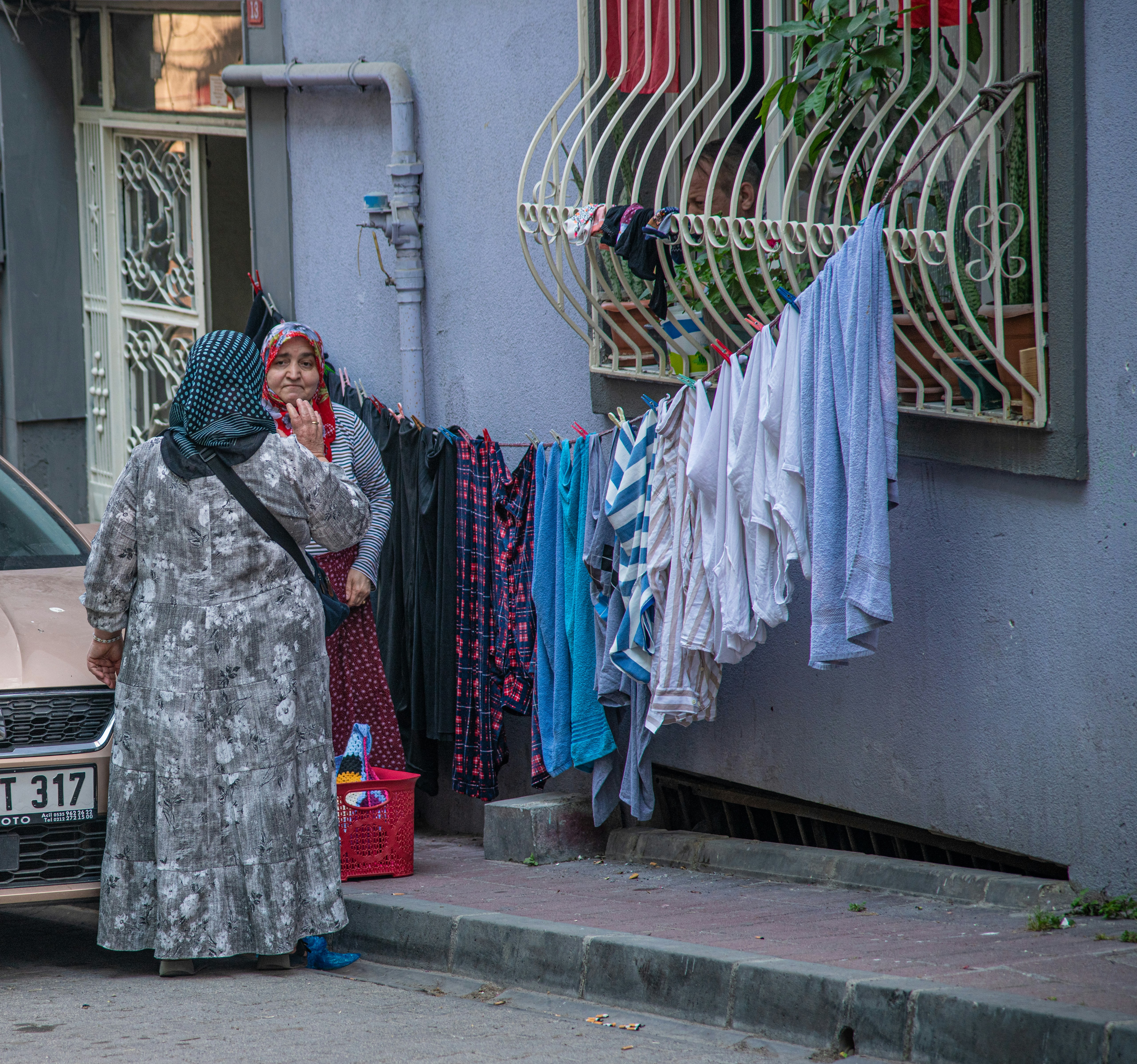 Two Women at a Laundry-Line Moment by a Quiet Urban Façade