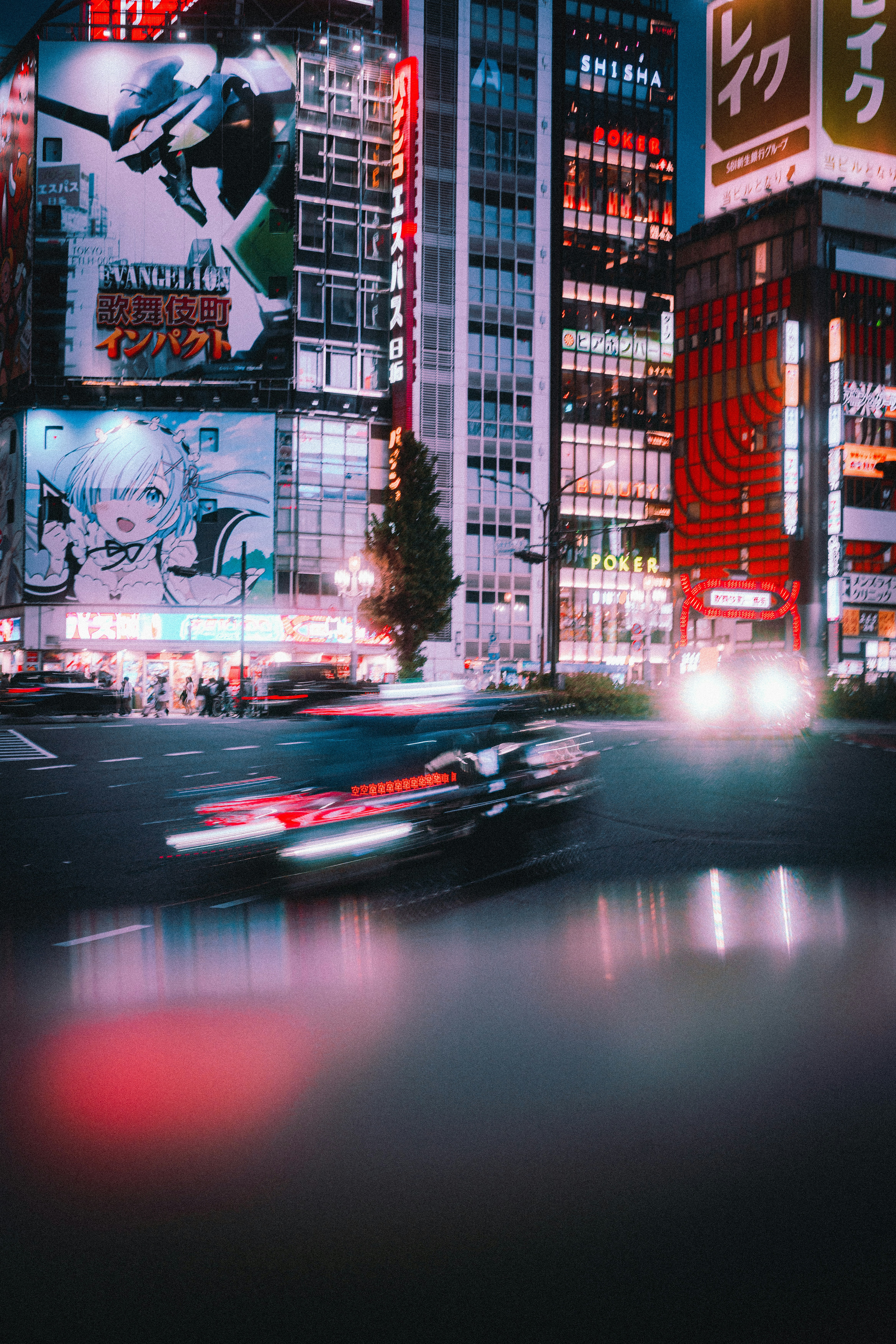Vibrant cityscape illuminated by neon signs, featuring a prominent anime-themed billboard amidst bustling traffic. 
