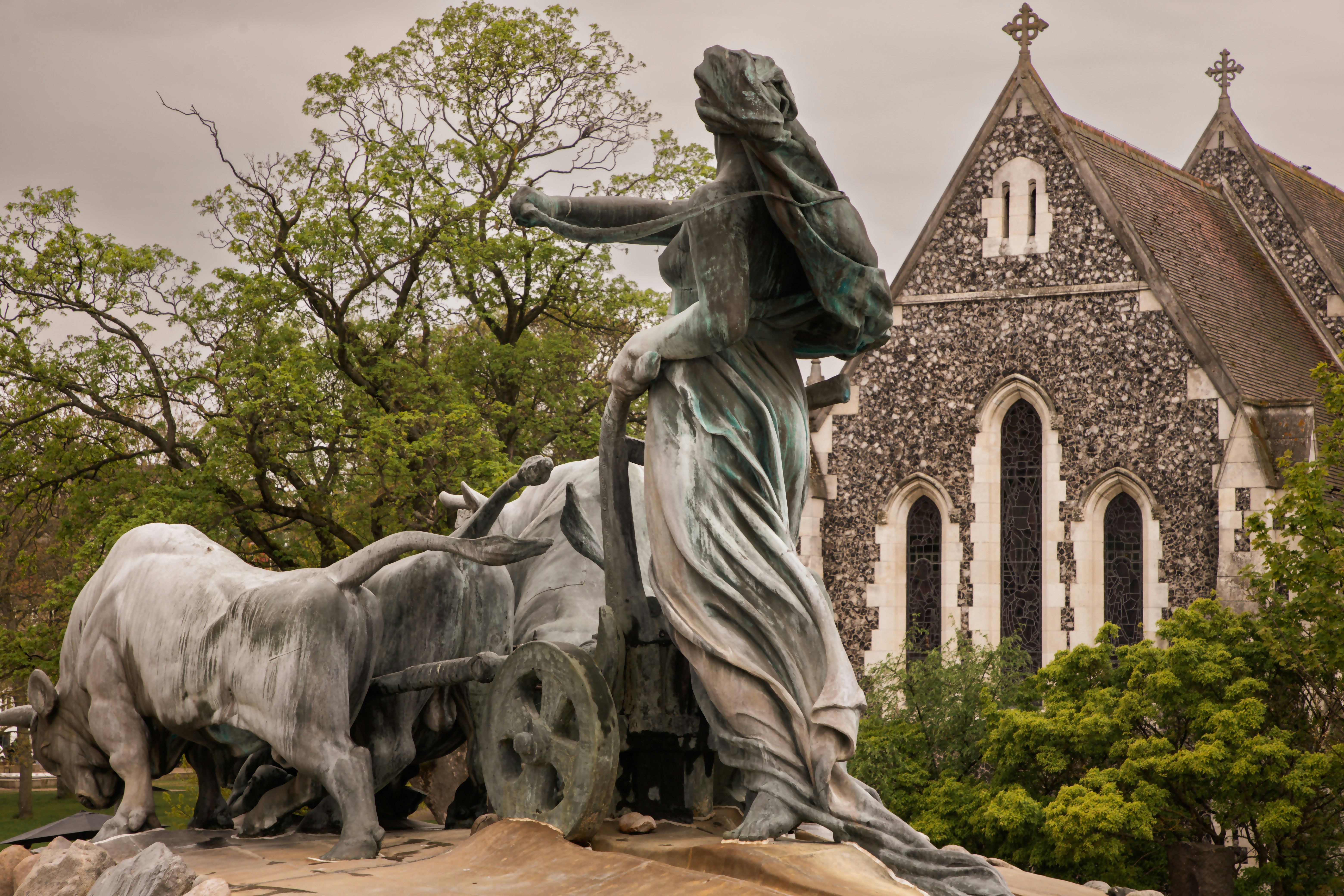 A statue of a woman with cows and a church. photo – Free Statue Image ...