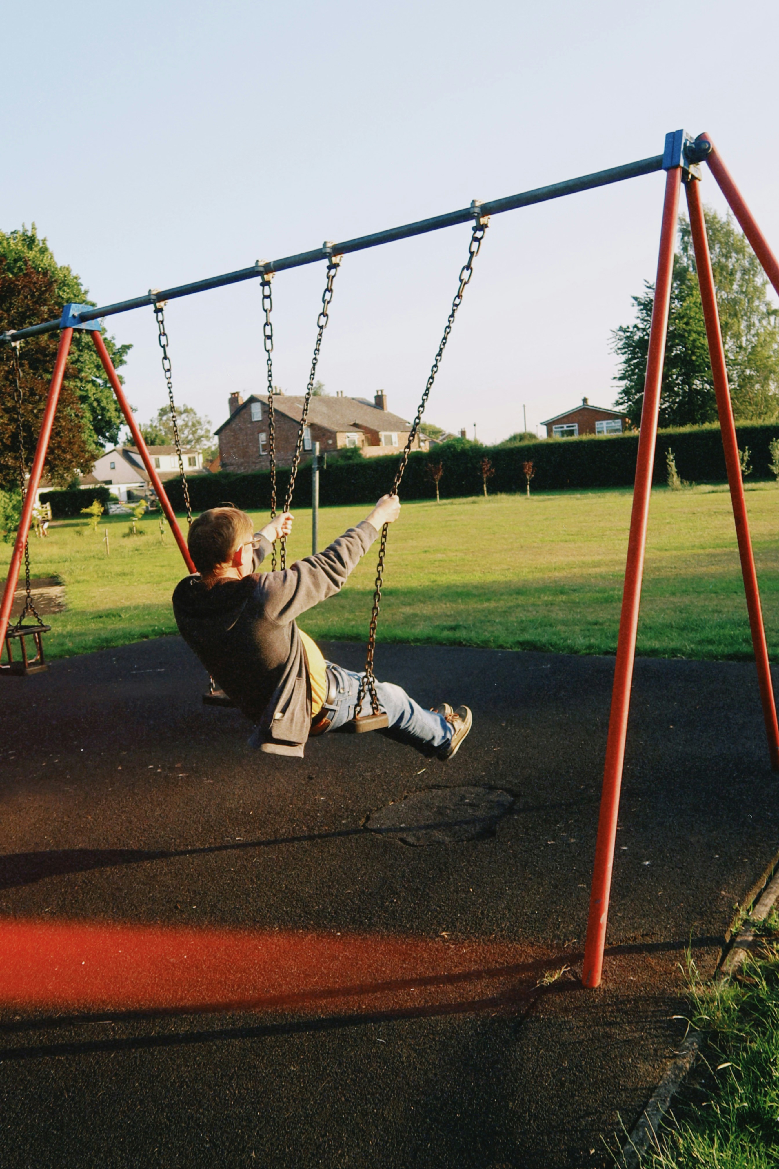 Boy is swinging high on a playground swing.