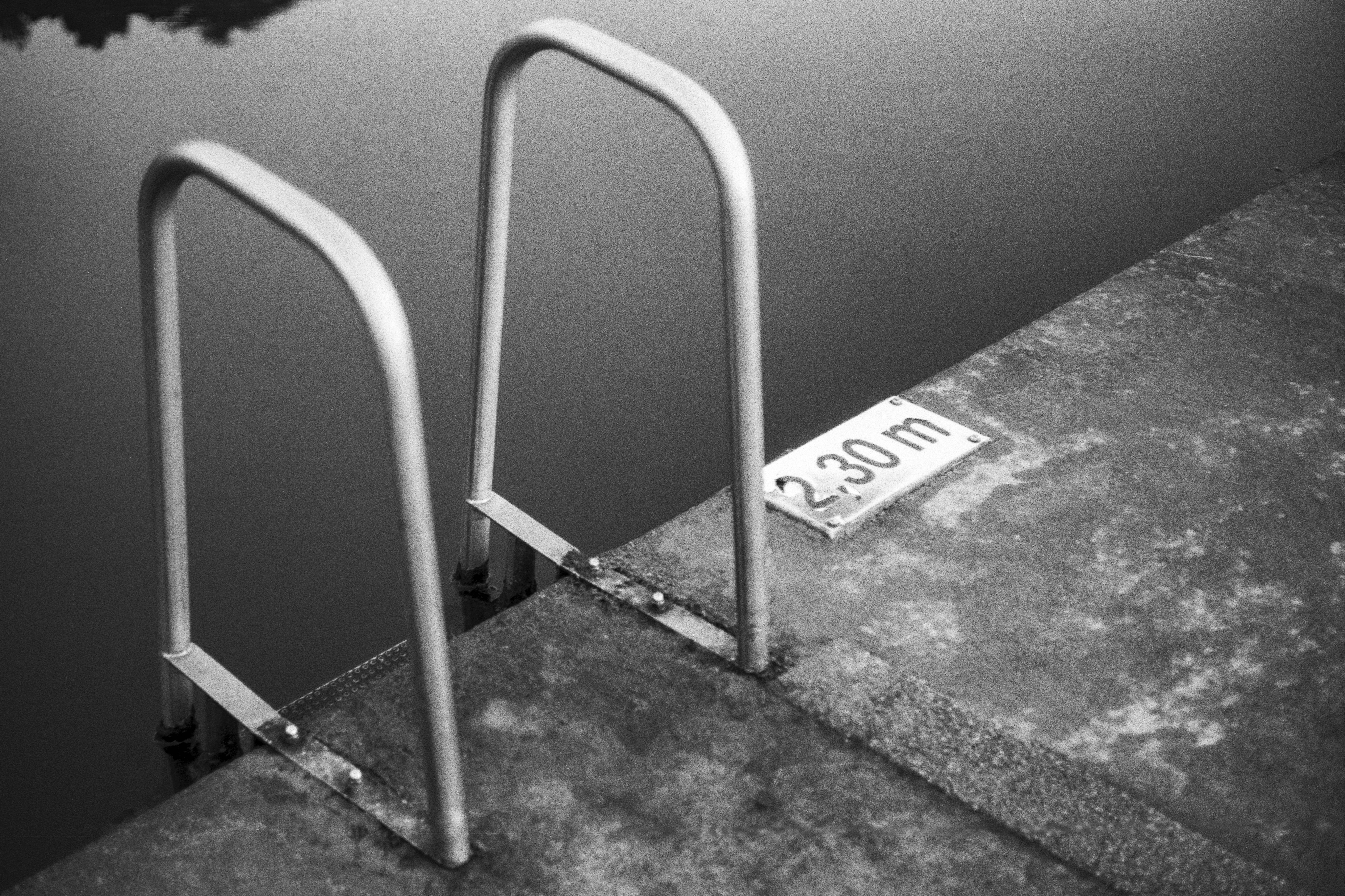Old diving ladder at the seawater pool in Dinard, France. Shot on Ilford HP5 with a Leica M3 and Summicron 50mm in October 2023. | Ladder leads into still water.