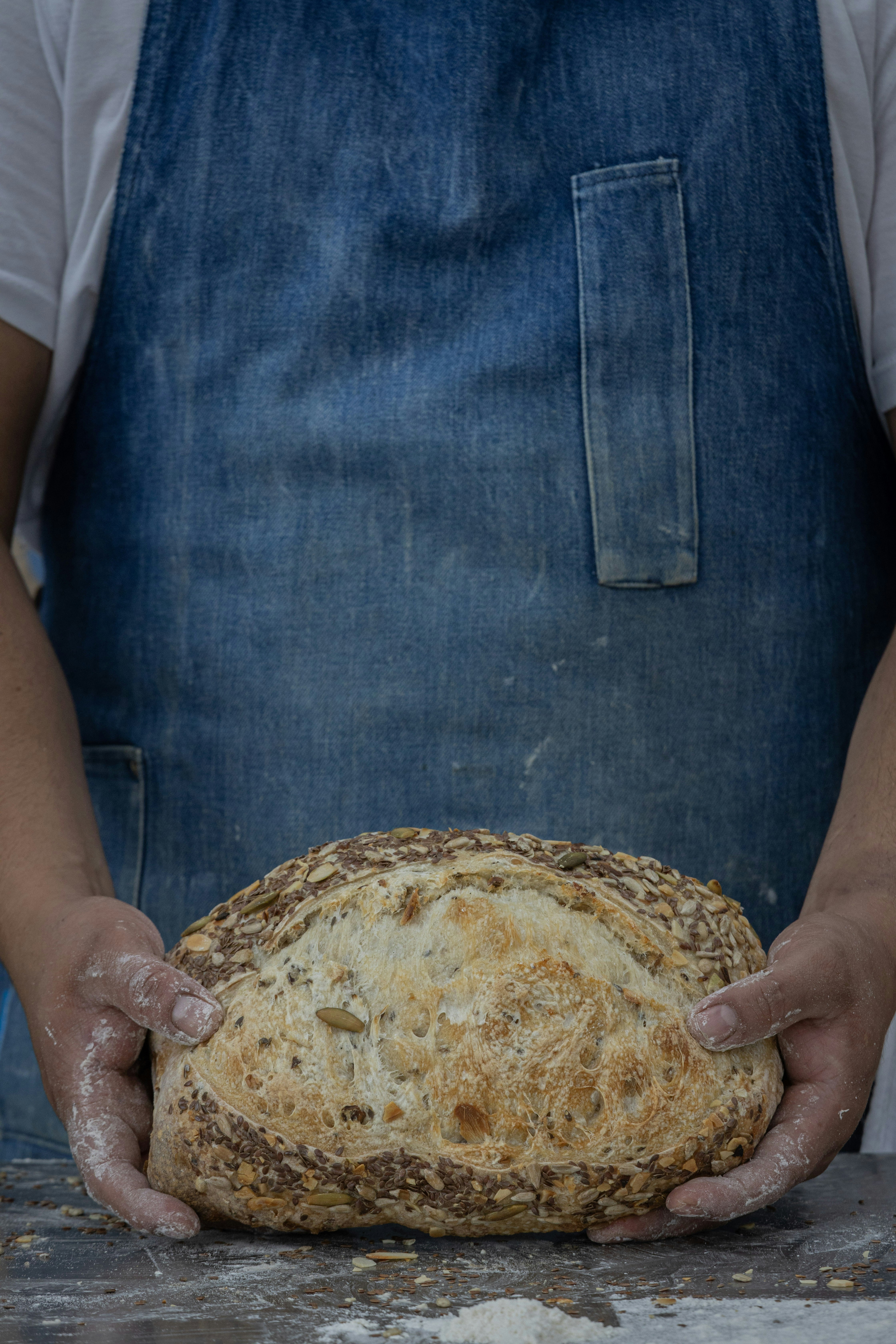 A baker holds a loaf of bread.