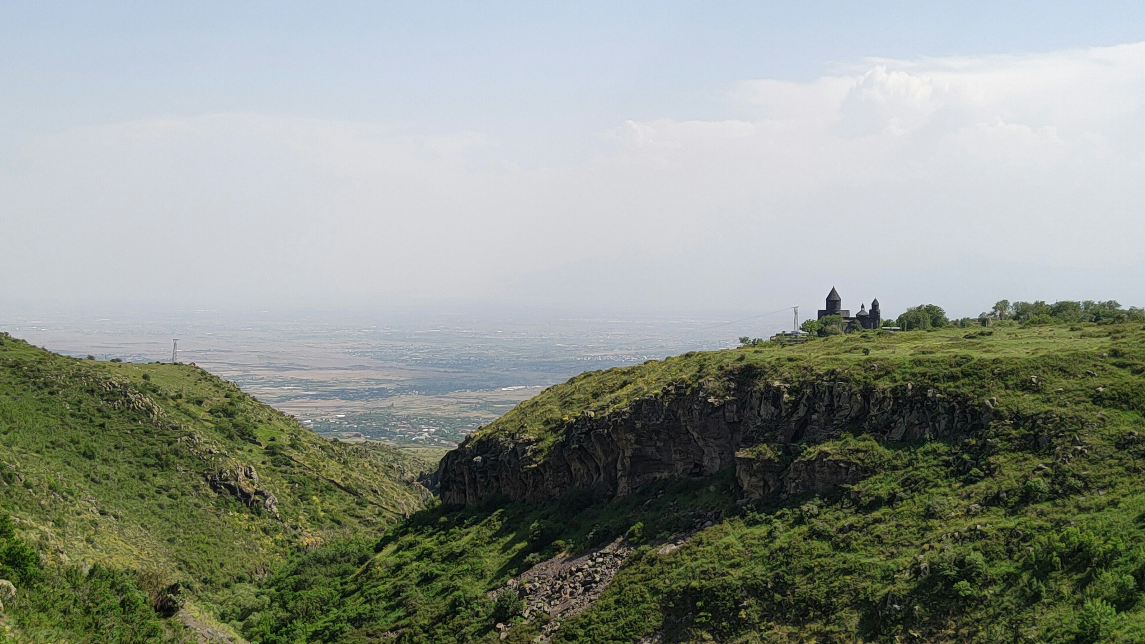 Hilly landscape with a distant structure is depicted.