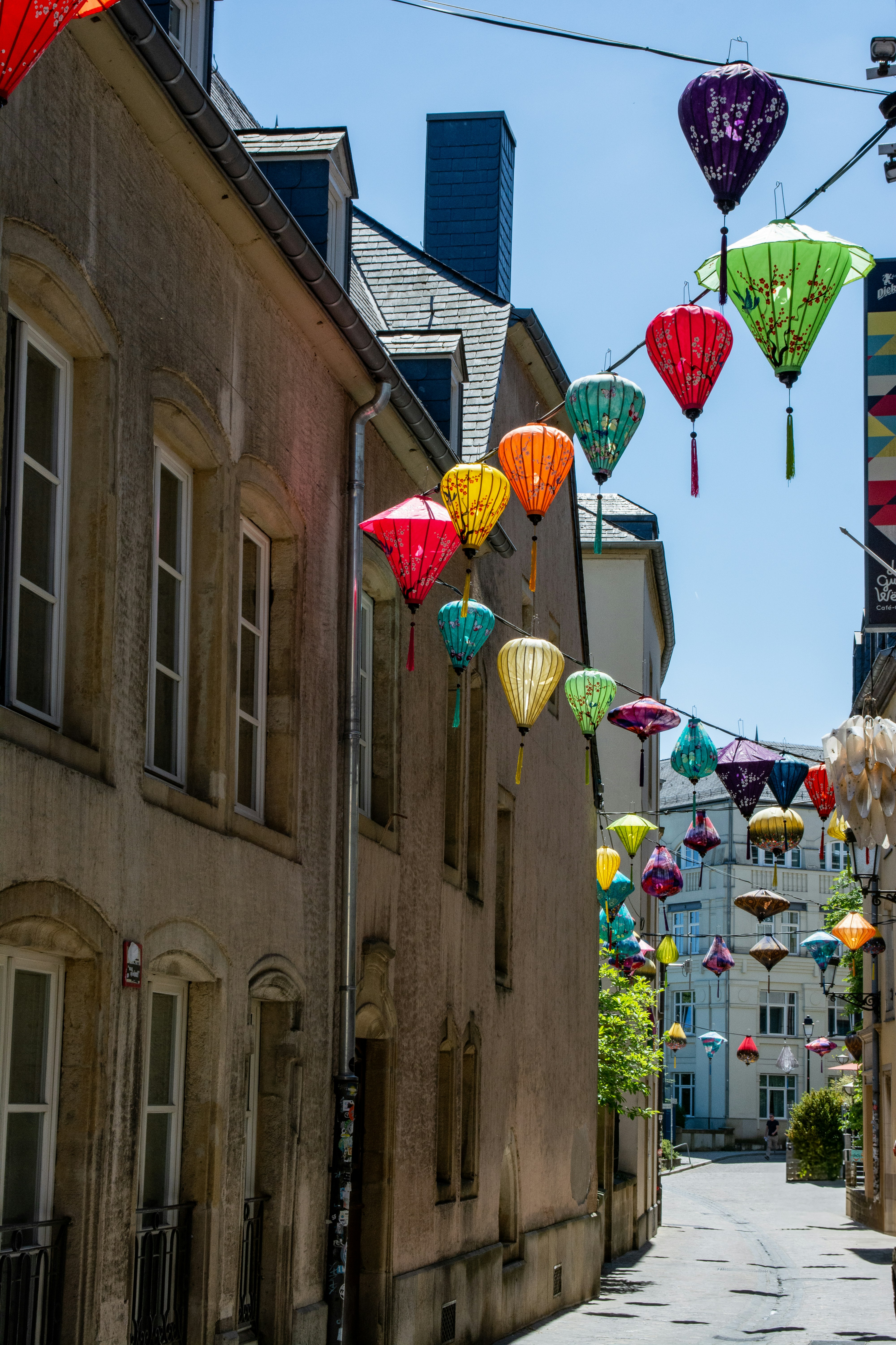 Prismatic Lanterns Draped Across a Sunlit European Alley