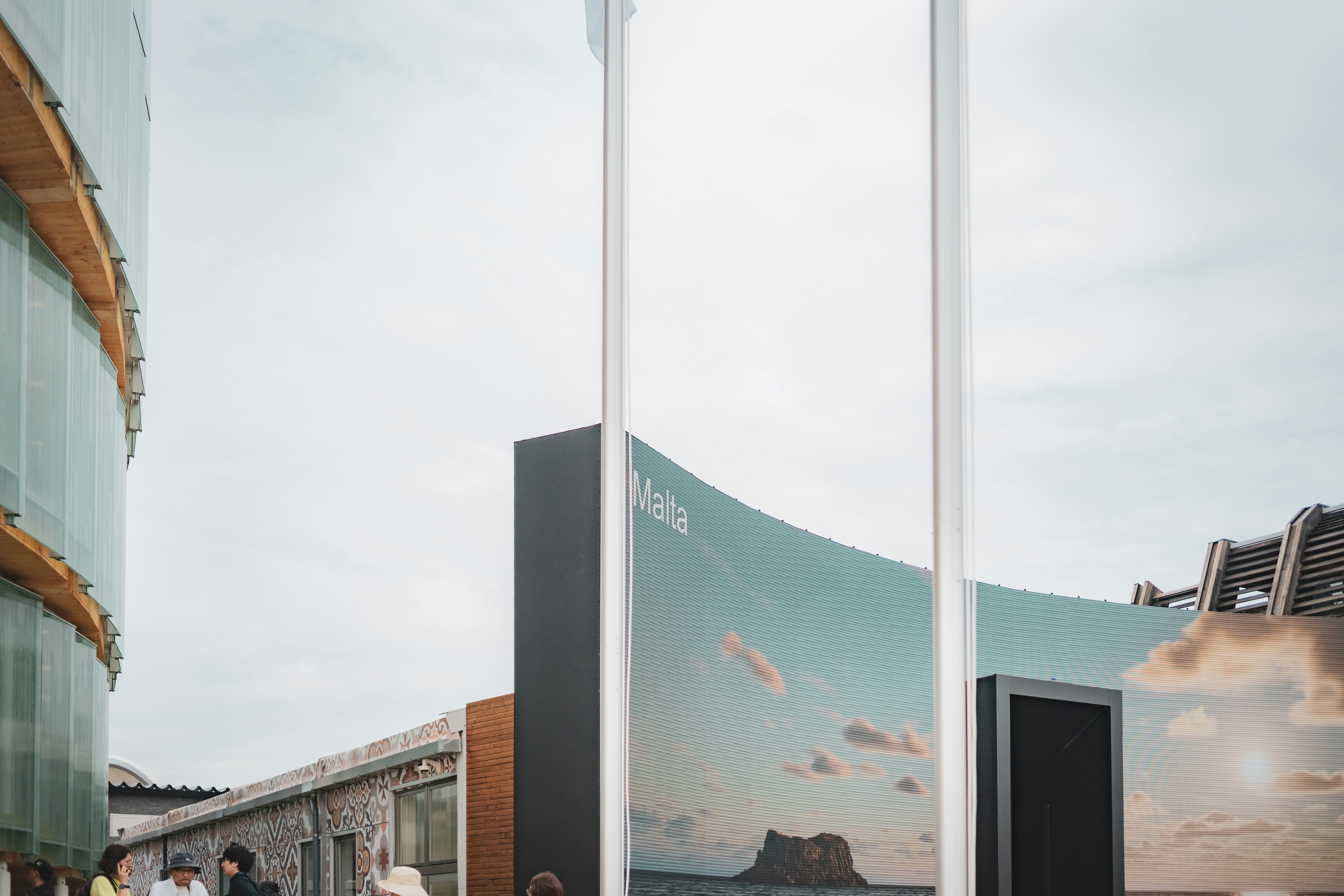 Promotional display showcasing Malta's scenic coastline, featuring a digital backdrop of clouds and water, with visitors engaging nearby.