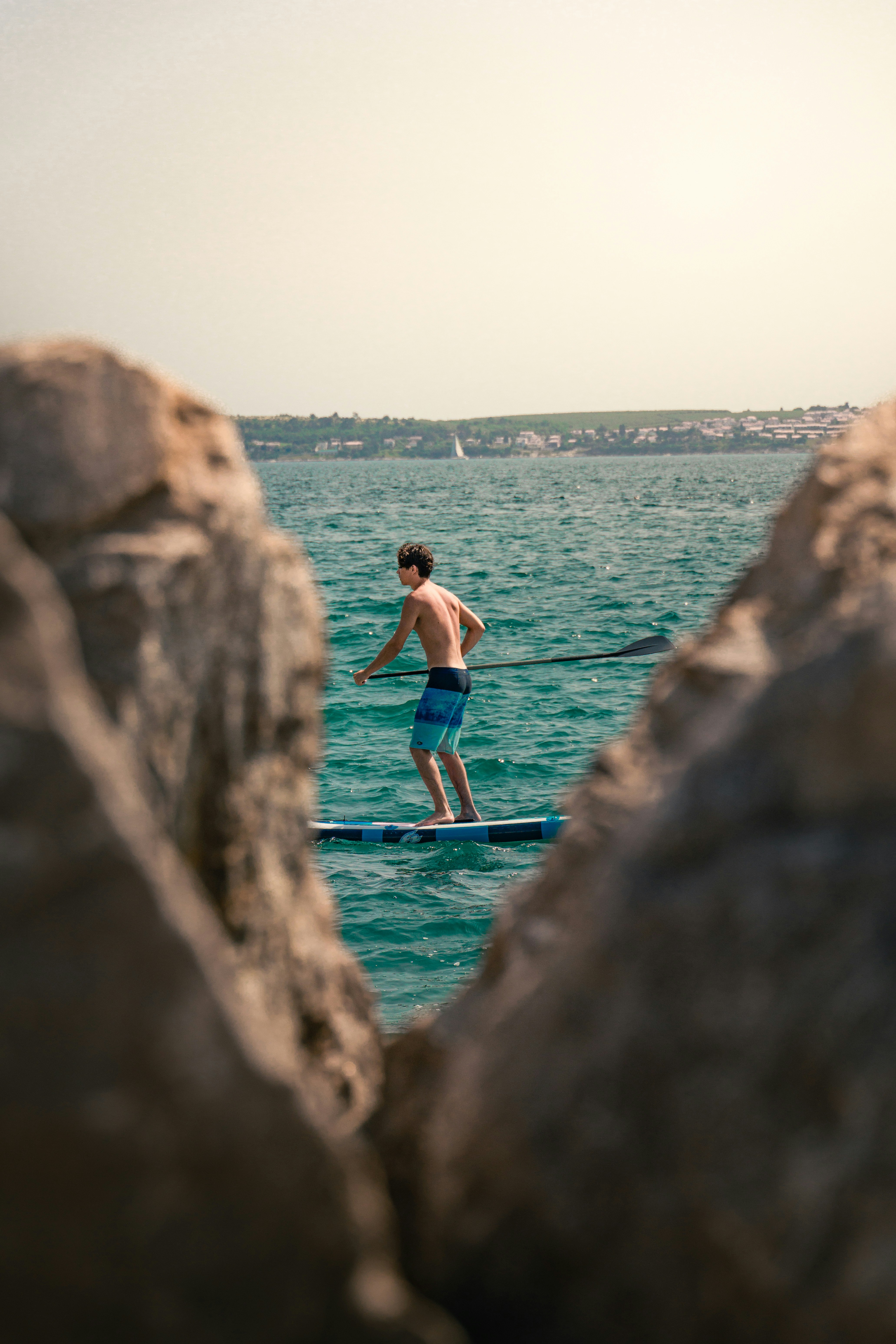 Between Stone Gate and Sea: A Solo Paddleboarder Navigates a Narrow Blue Corridor