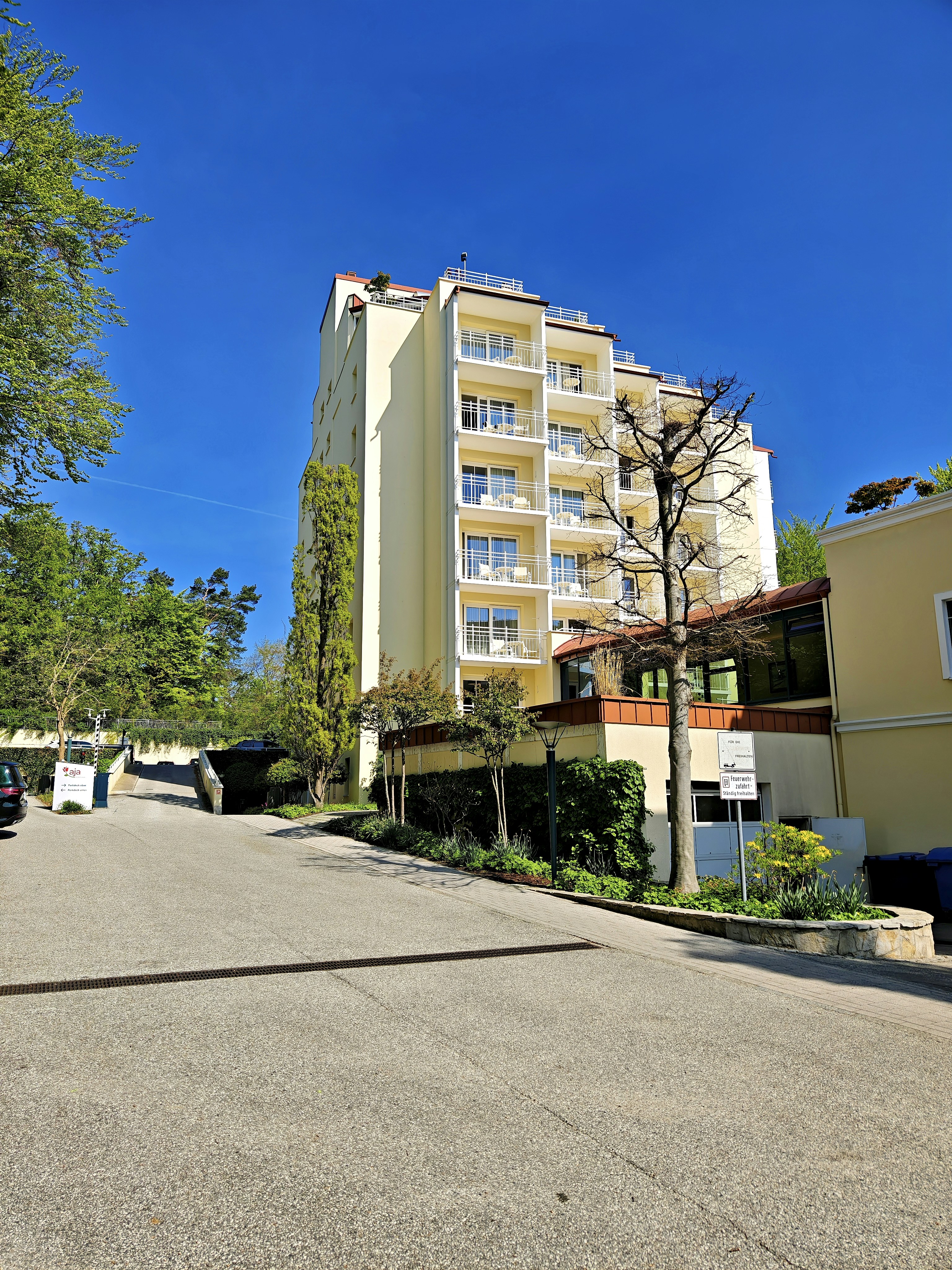 Contemporary building nestled among lush greenery, showcasing a blend of architecture and nature. The scene captures a tranquil urban environment.