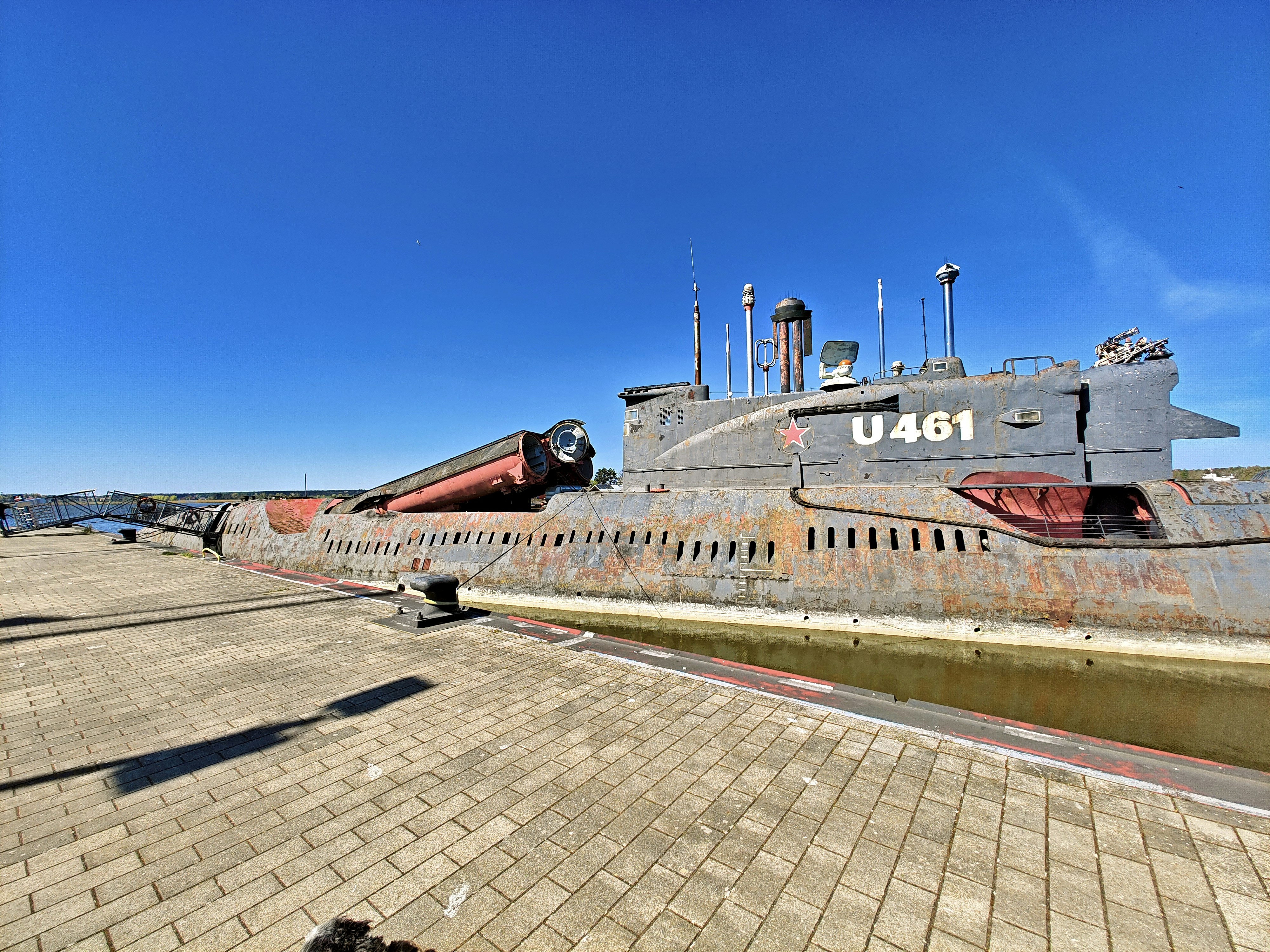 Cold Steel at the Dock: A Rusted Submarine Lounges by the Quay