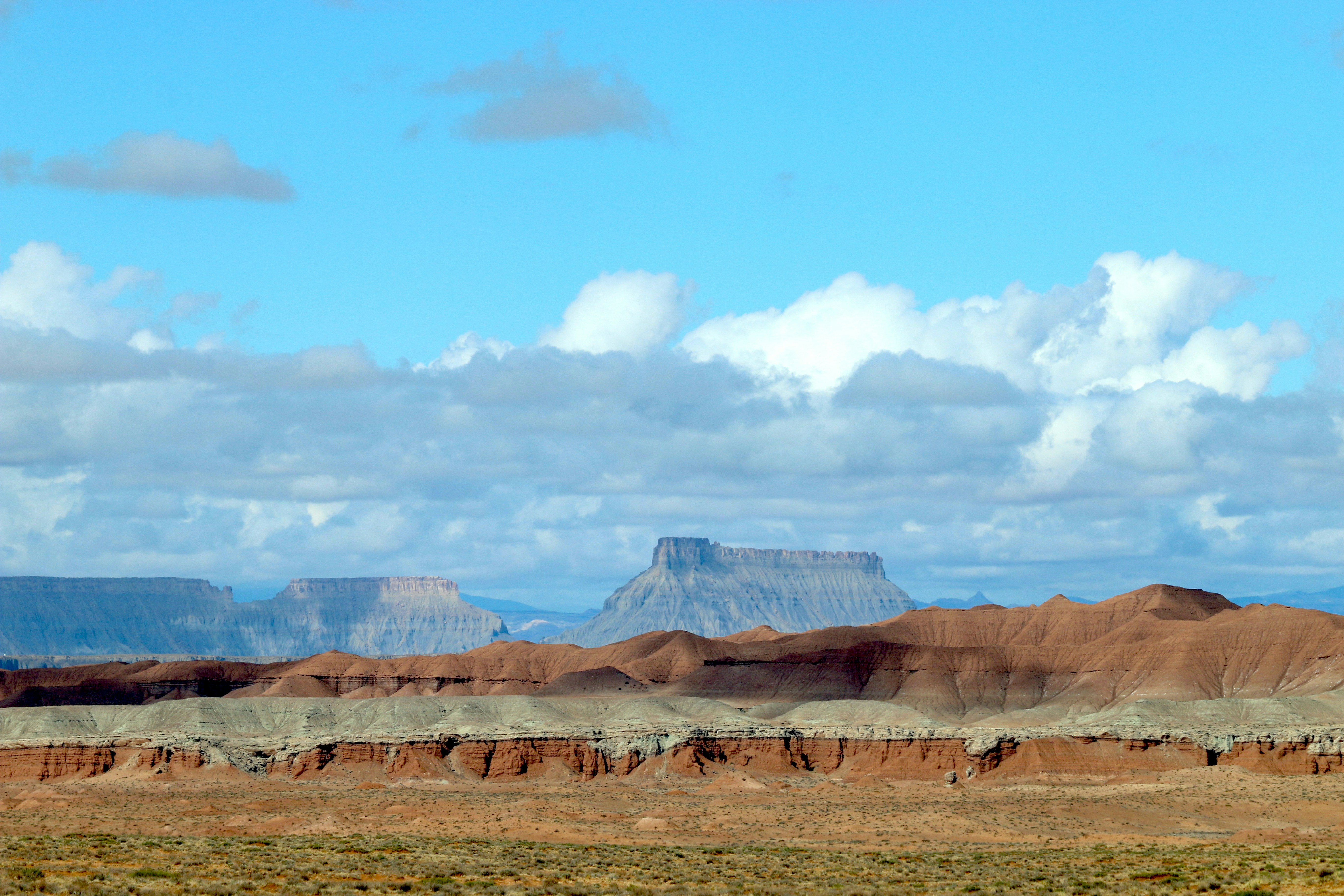 Vast desert landscape showcasing layered rock formations under a dynamic sky filled with clouds.