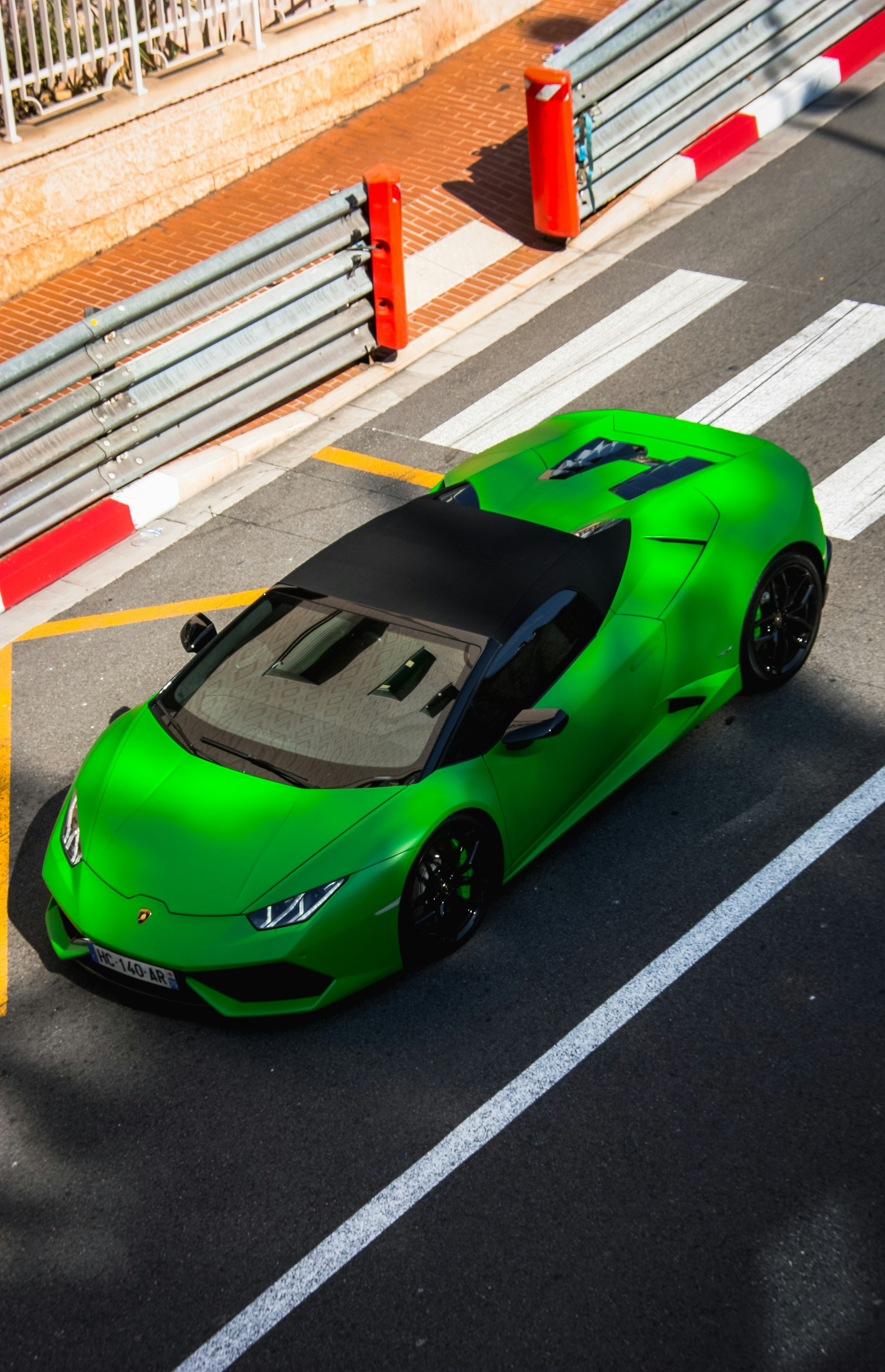Lime Lamborghini on a sunlit street circuit beside guardrails
