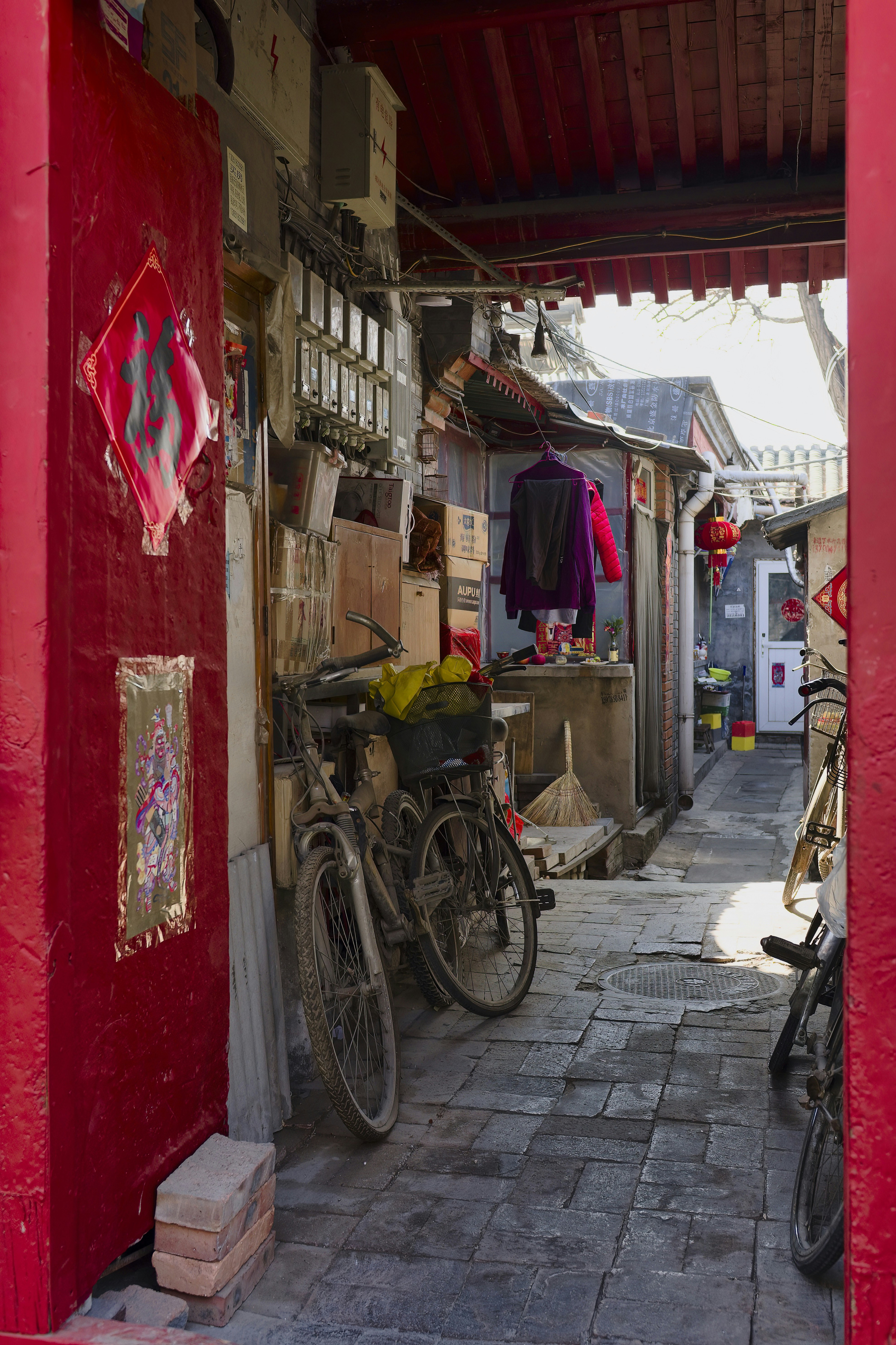 Narrow alleyway in a traditional neighborhood featuring bicycles, vibrant decorations, and a glimpse of daily life. The scene captures the essence of local culture and history.