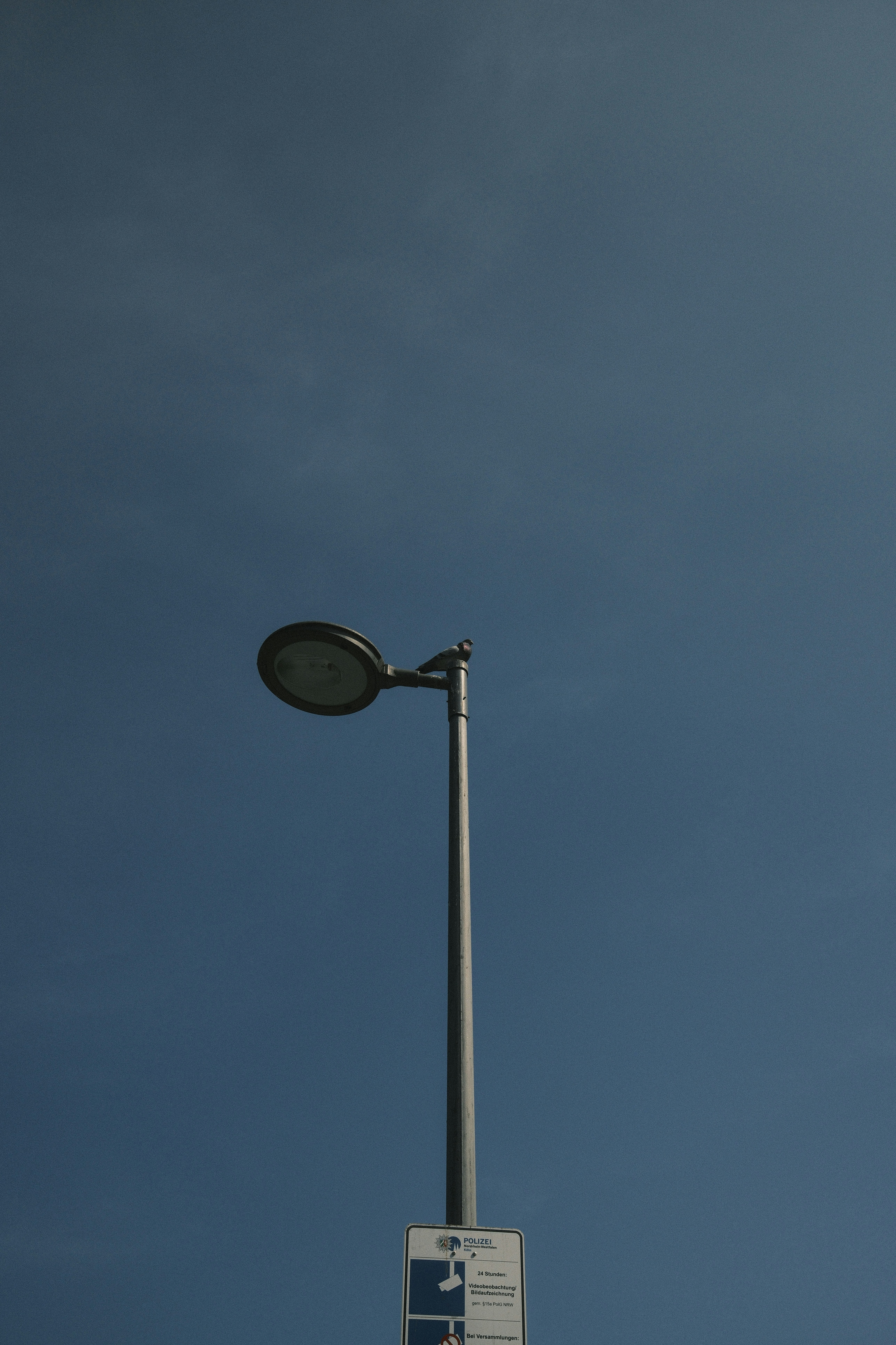 A lamp post stands against a clear blue sky.