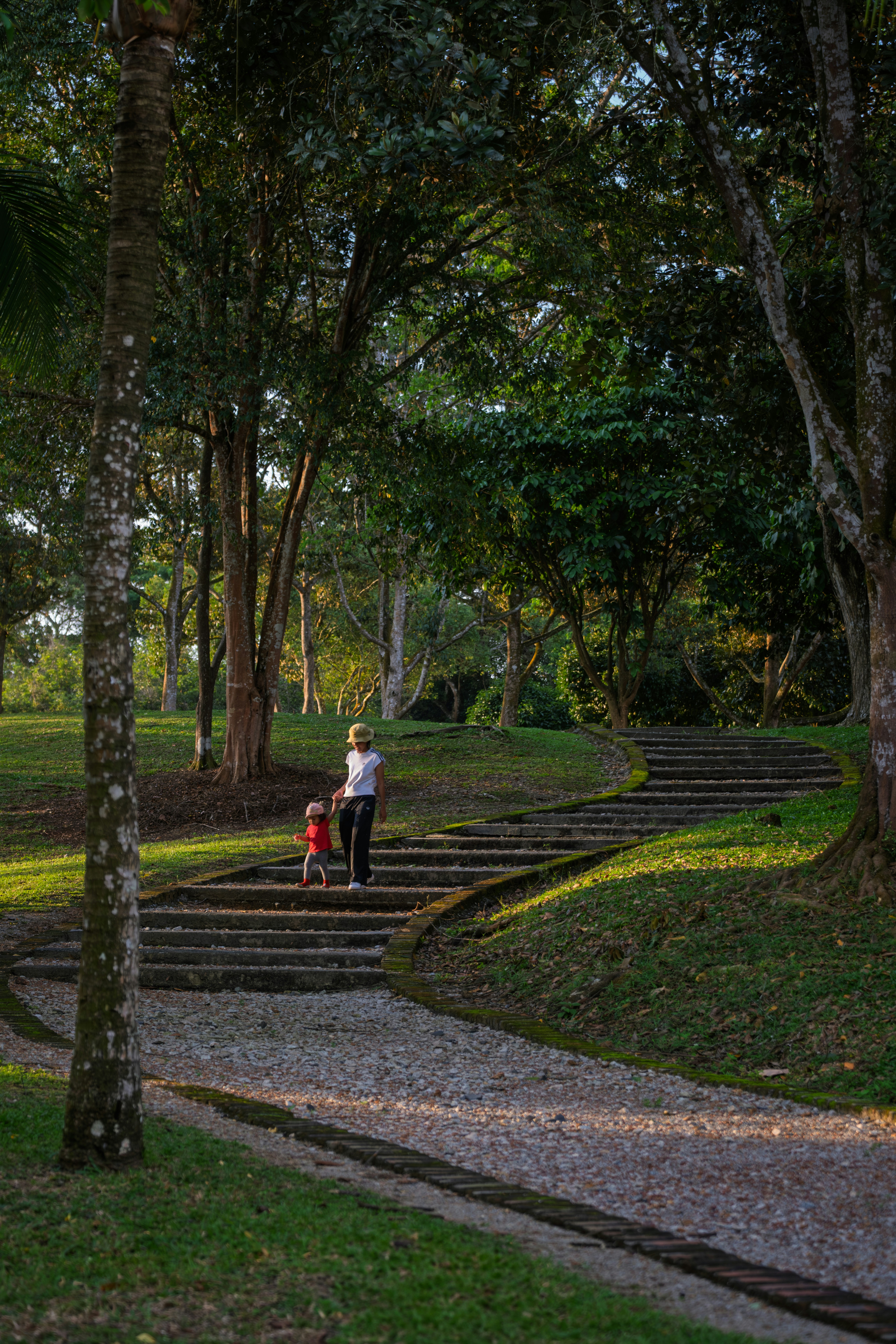 A woman and child walk up steps in a park.