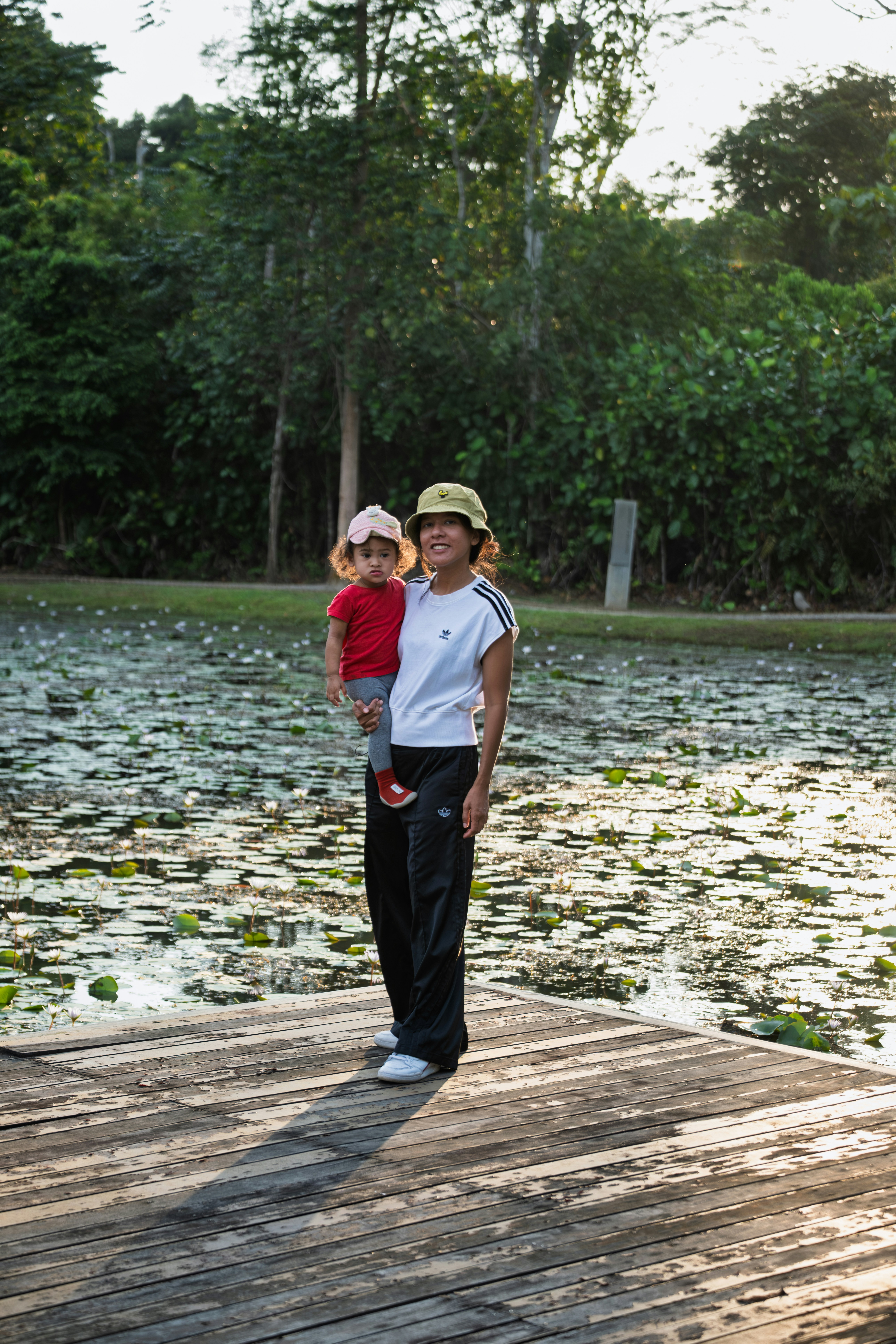 Mother and Child on a Weathered Dock by a Lily-Pad Lake