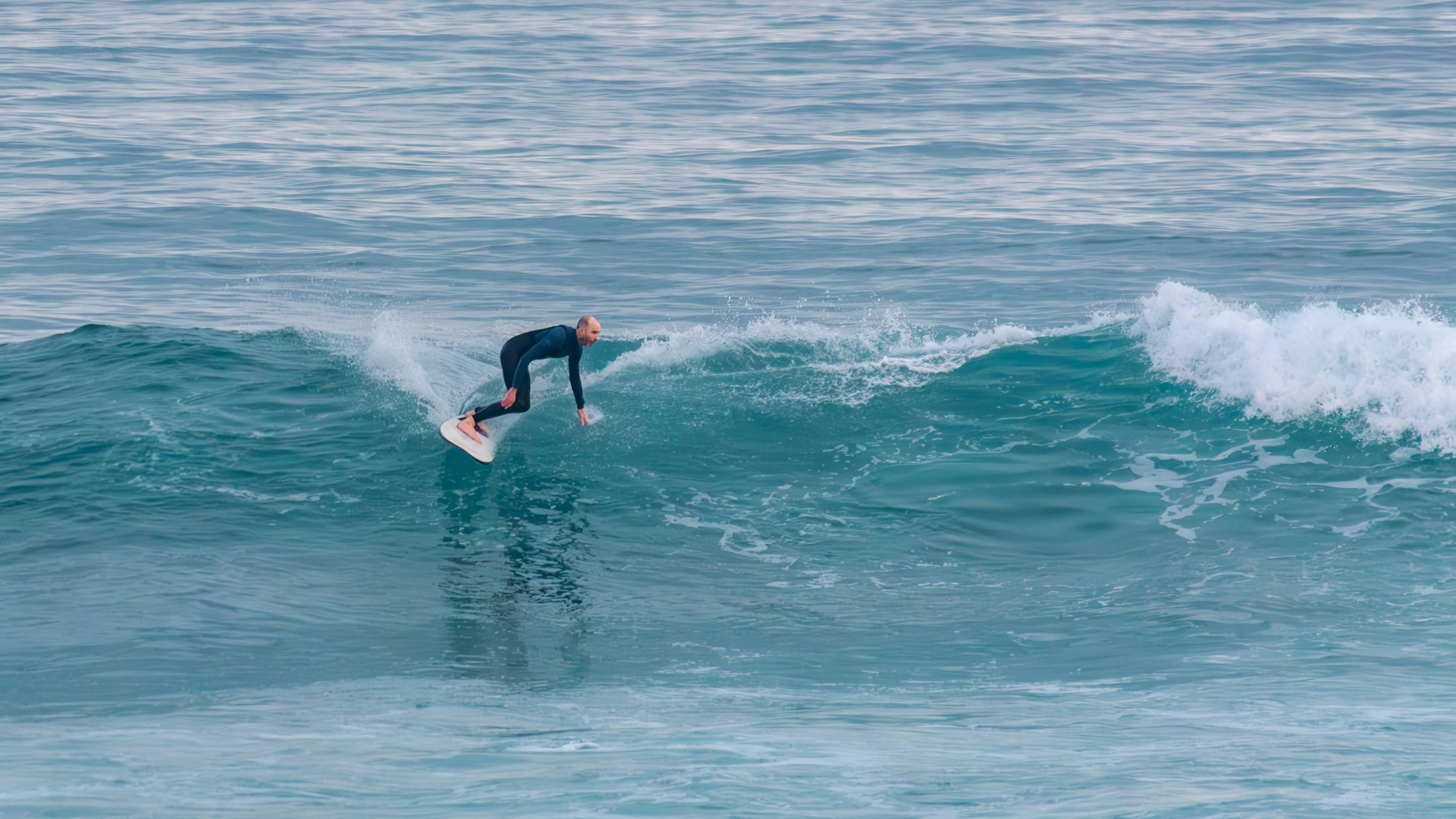Carving the turquoise crest: a lone surfer tames a curling wave