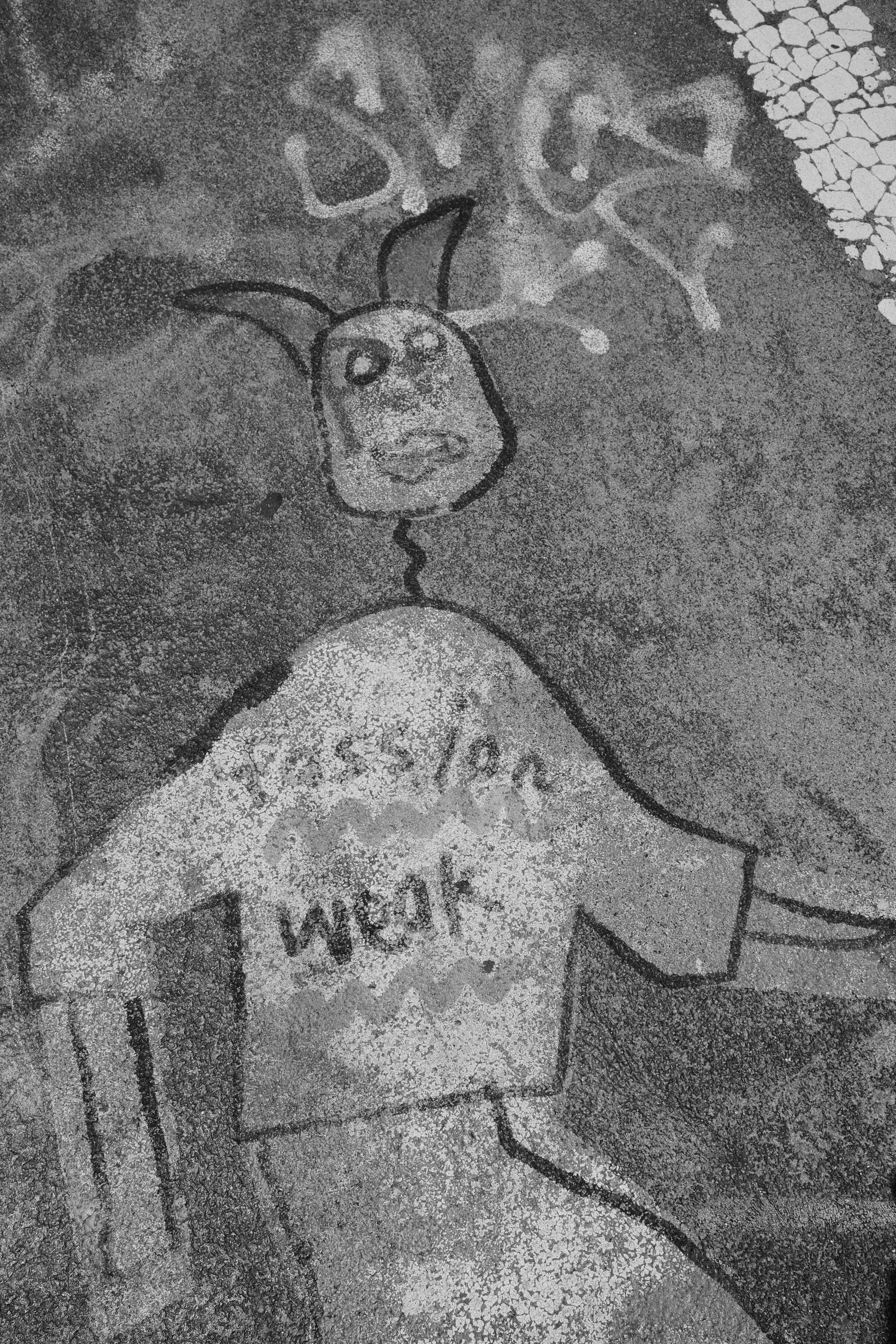 Graffiti Portrait on Weathered Wall: A Surreal Cartoon Figure in Grainy Monochrome