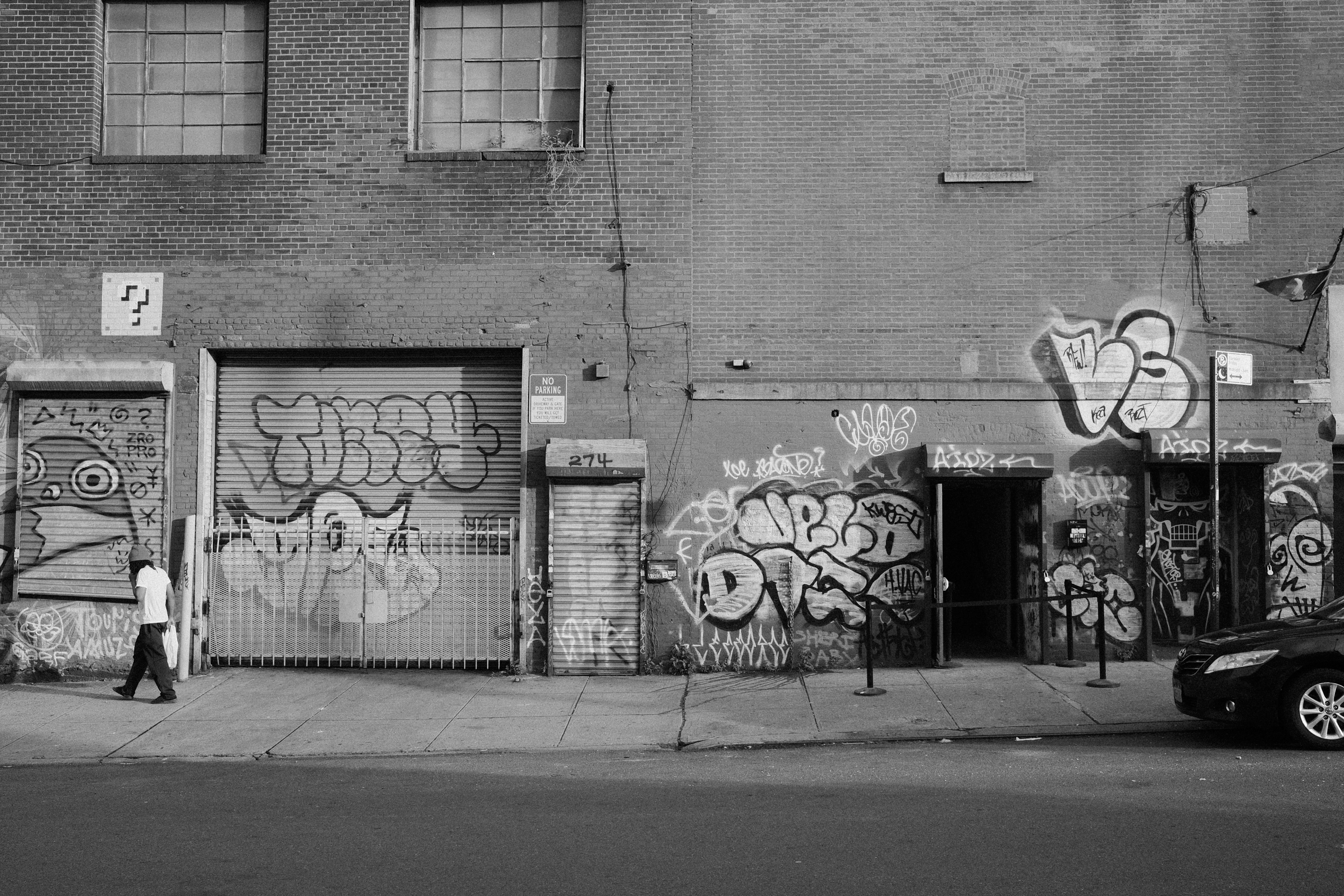 Colorful graffiti adorns the walls of a city block, showcasing urban artistry and expression. A lone figure walks past the vibrant murals.