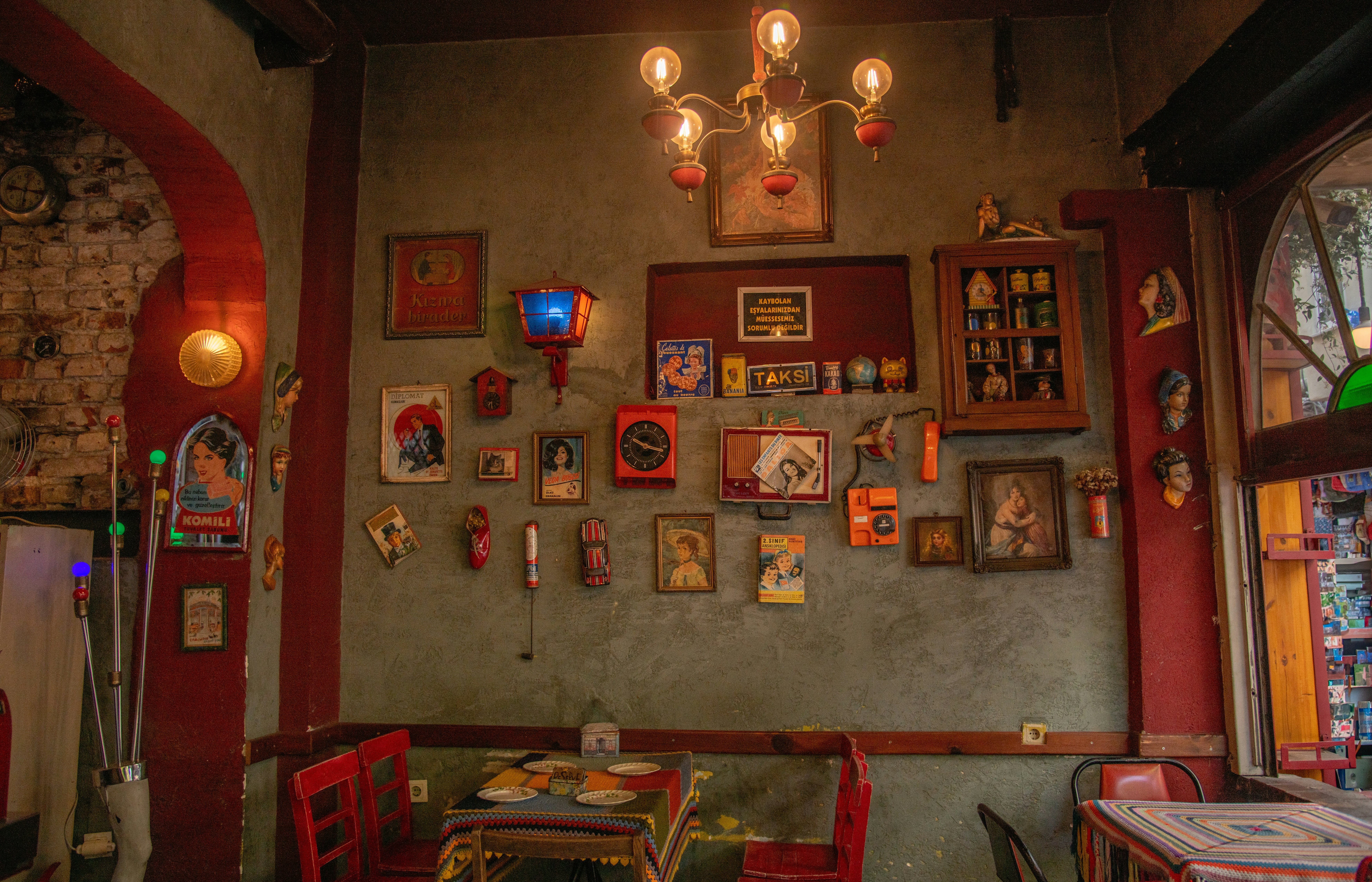 Eclectic wall adorned with vintage memorabilia and colorful decor in a cozy café setting.
