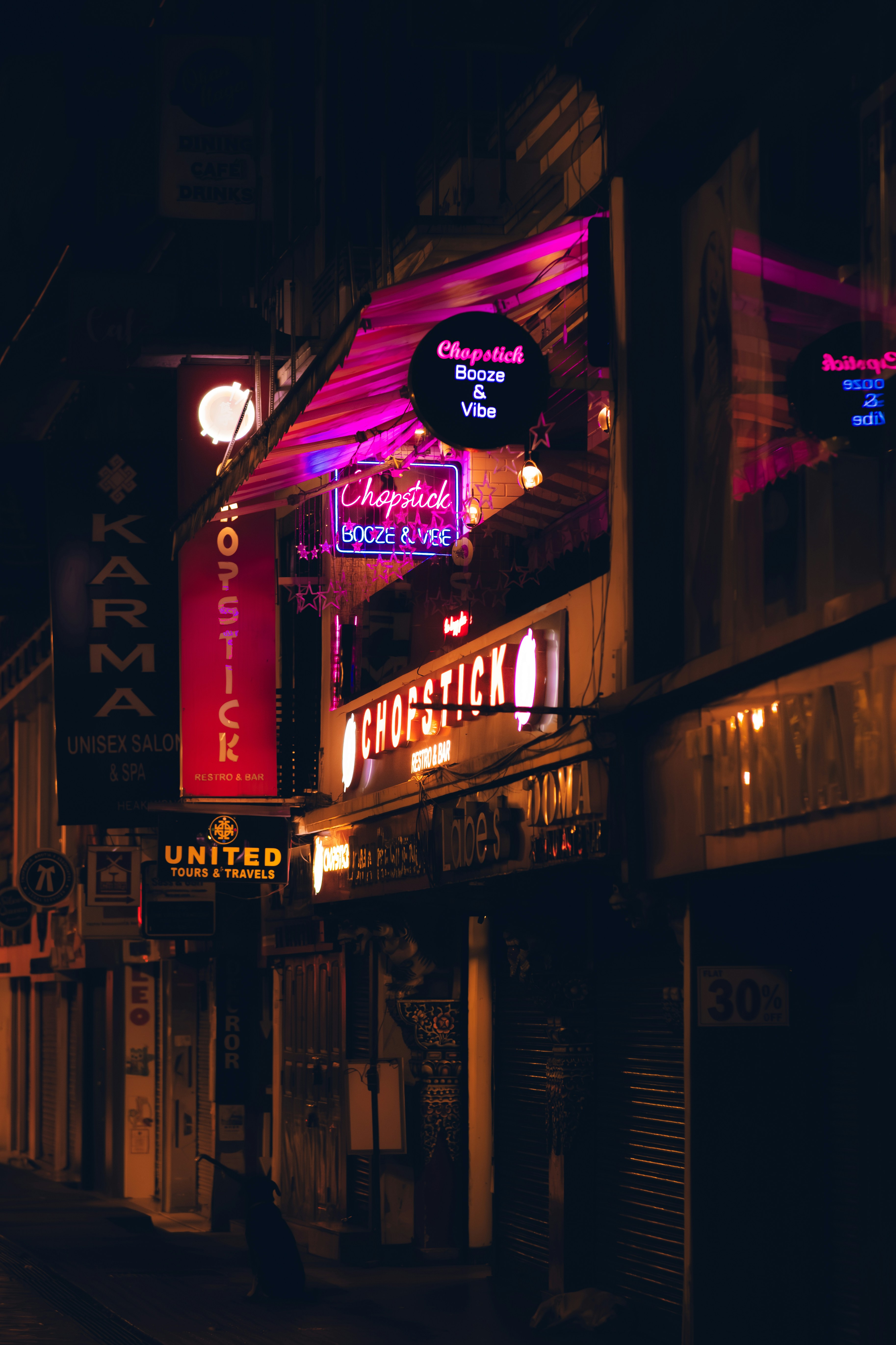 Neon signs light up a night street.