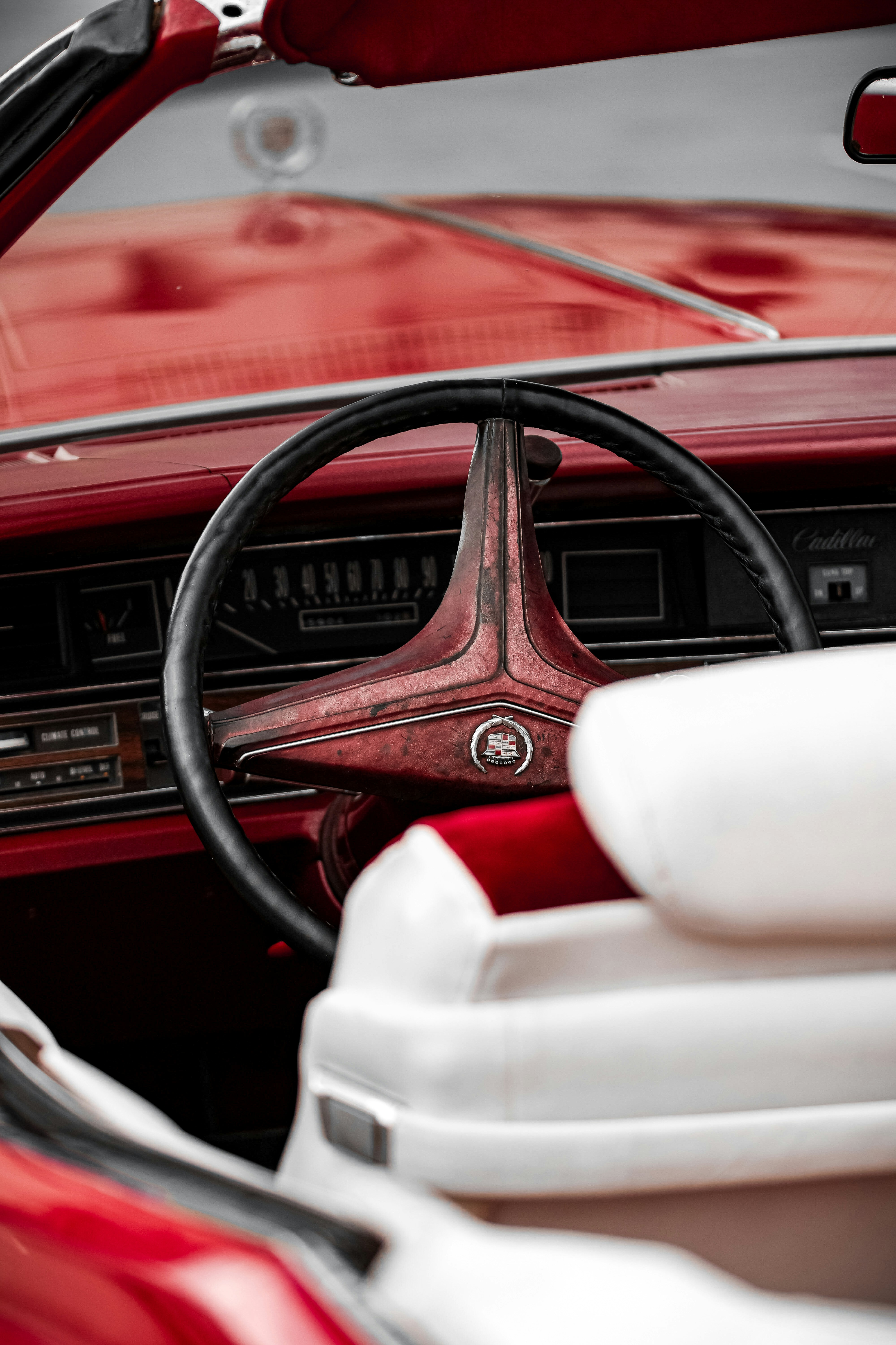 Interior of a vintage Cadillac showcasing a luxurious steering wheel and plush seating. The rich red and white color scheme highlights the vehicle's classic design.