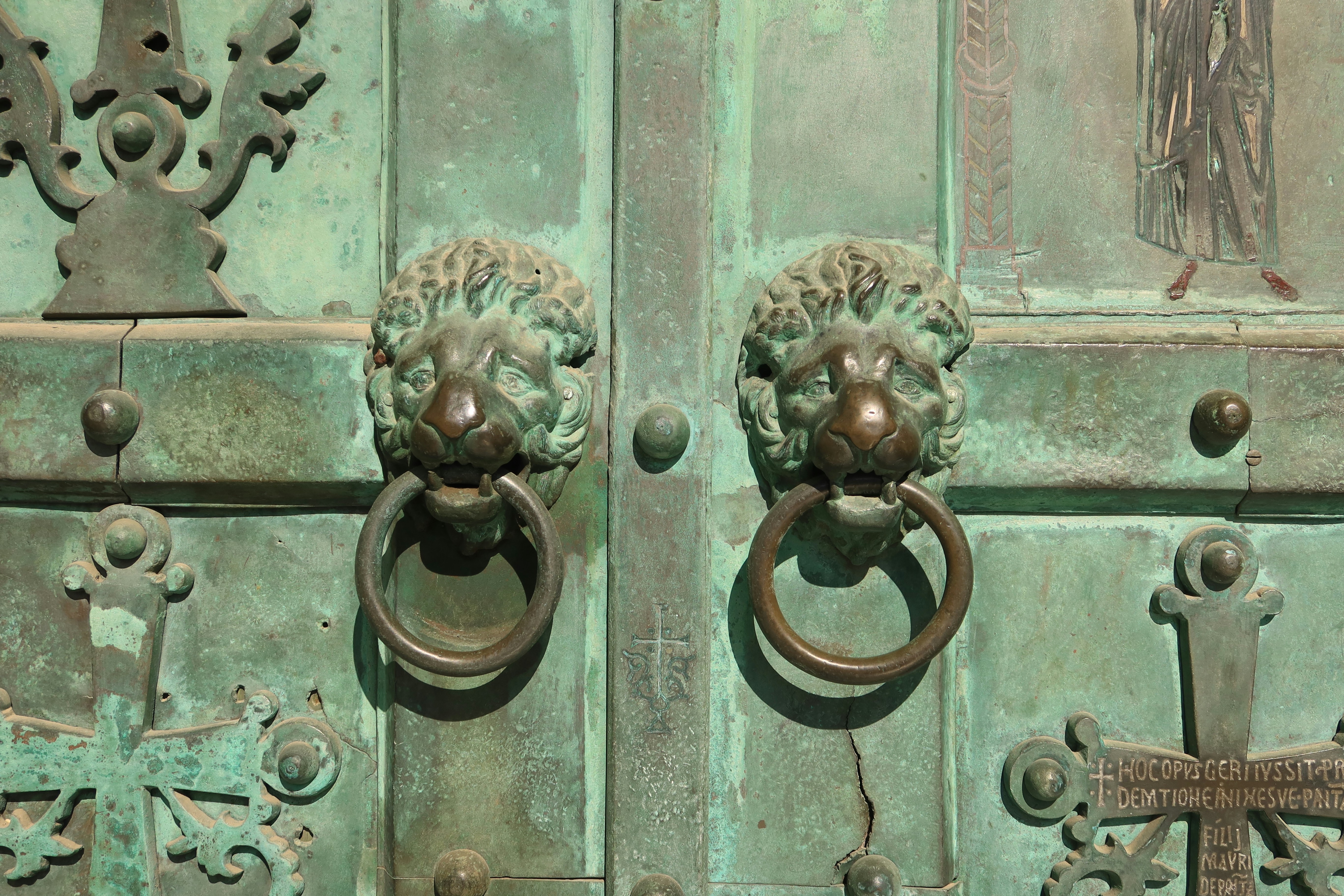 Lion-shaped door knockers adorn a weathered green door.
