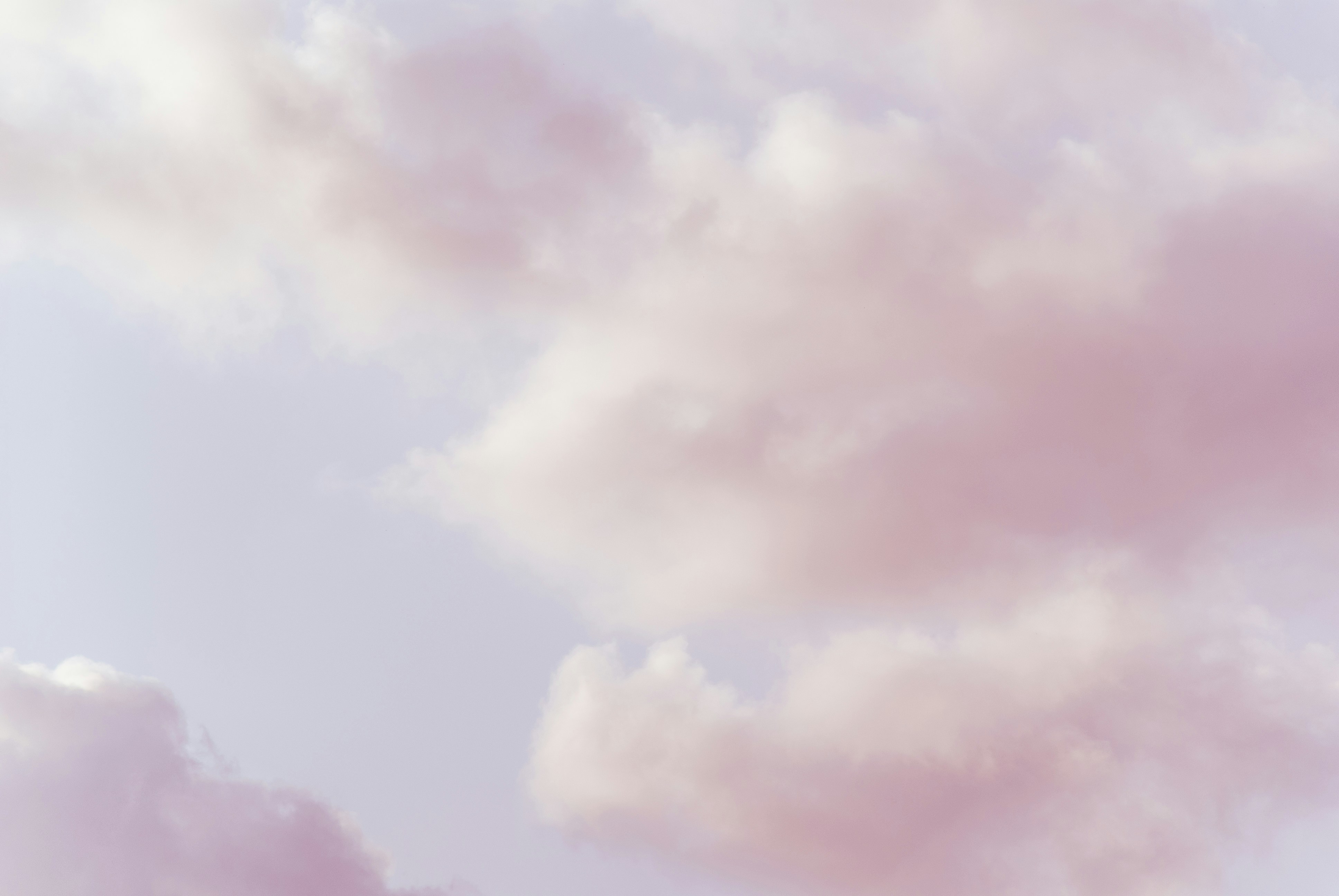 Soft, fluffy clouds drift across a gentle pastel sky, blending hues of pink and lavender. The ethereal atmosphere evokes a sense of calm and serenity.