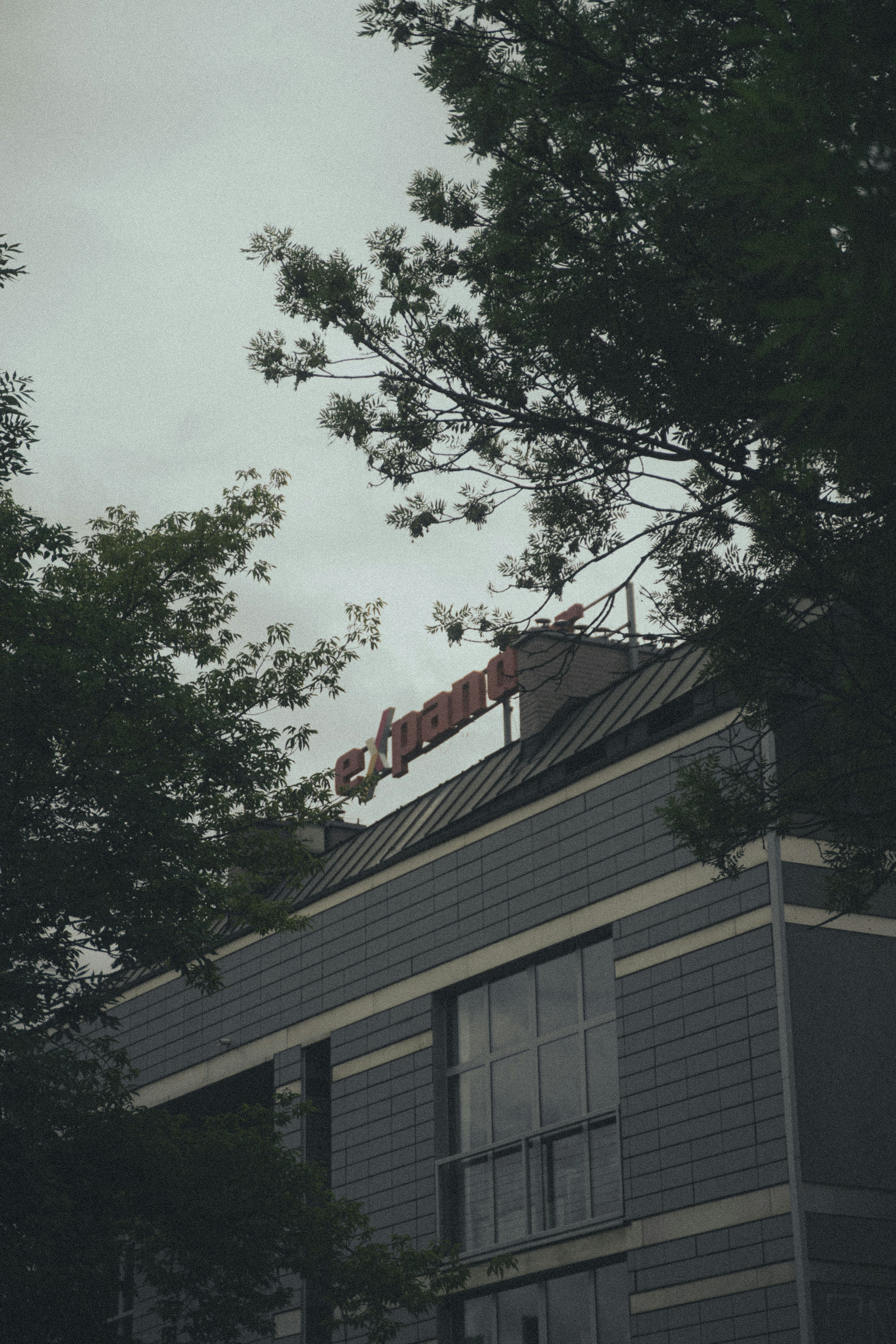 Film like view of company expander. | Building with "expand" sign on a cloudy day.