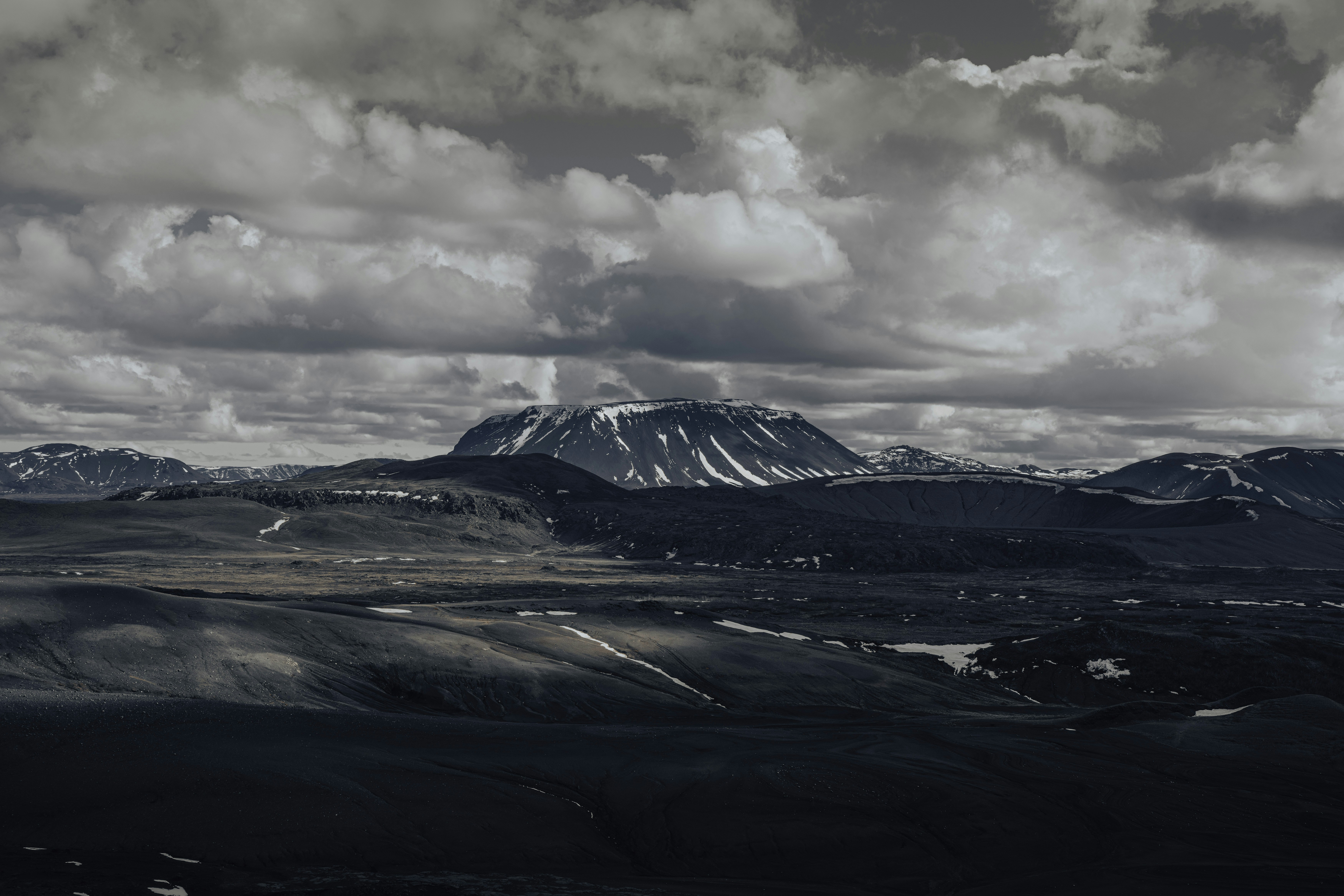 Dramatic clouds loom over a snowy mountain.