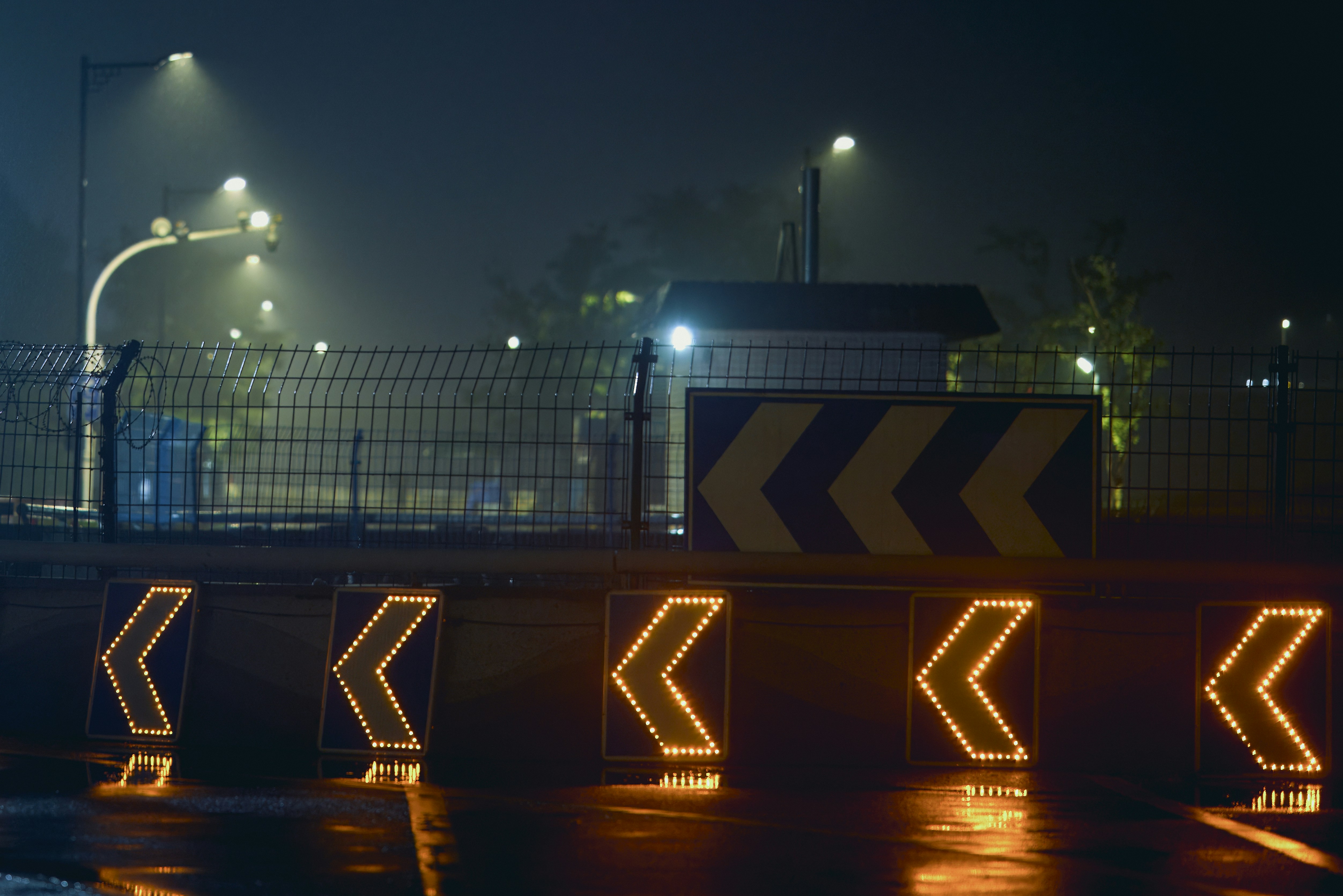 Neon Arrows on a Wet Night: Reflections Along a Barricade