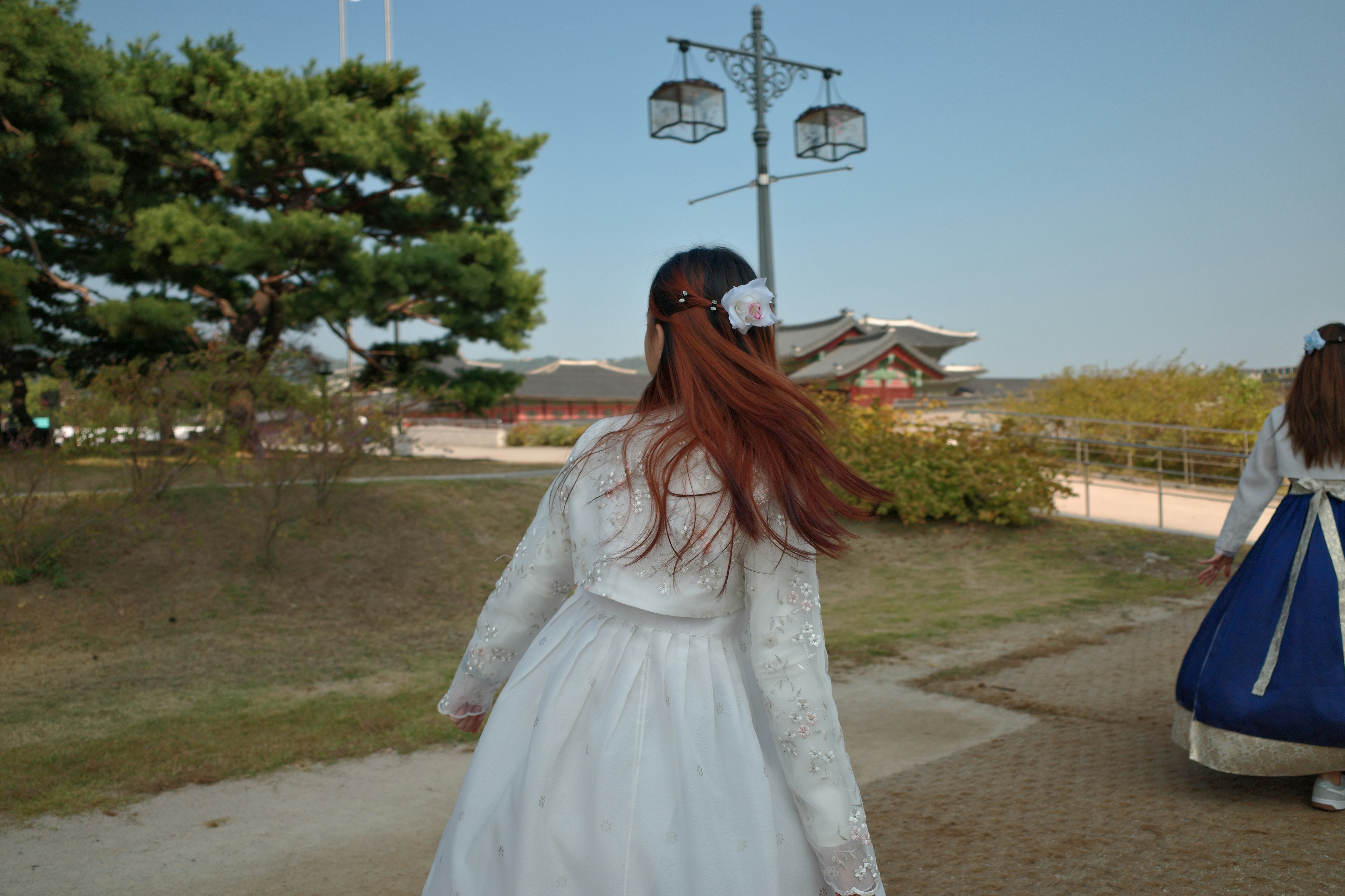 People in traditional clothing walk outdoors.