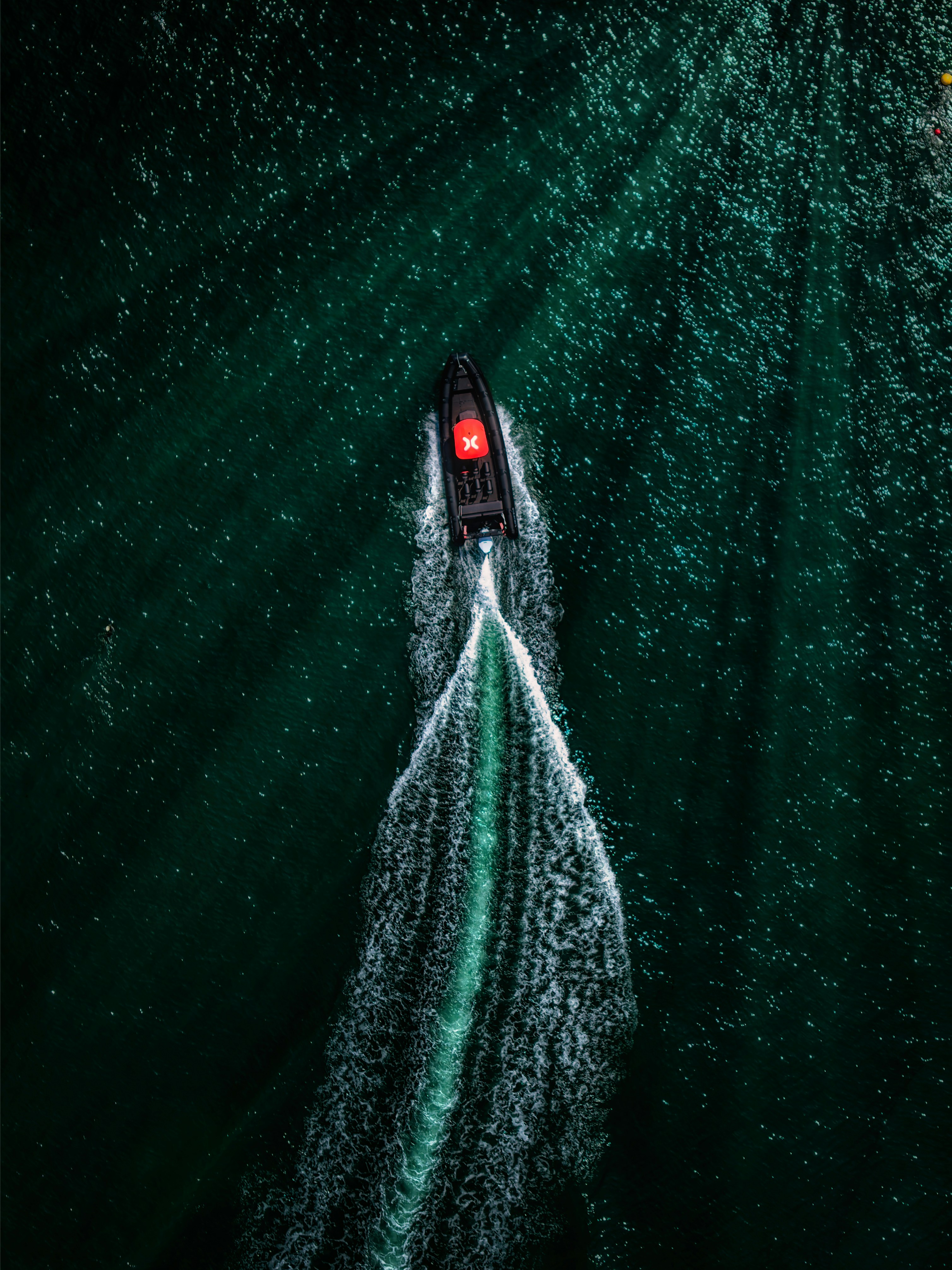 Verdant Wake: Aerial Glimpse of a Speedboat Cutting Through Teal Waters