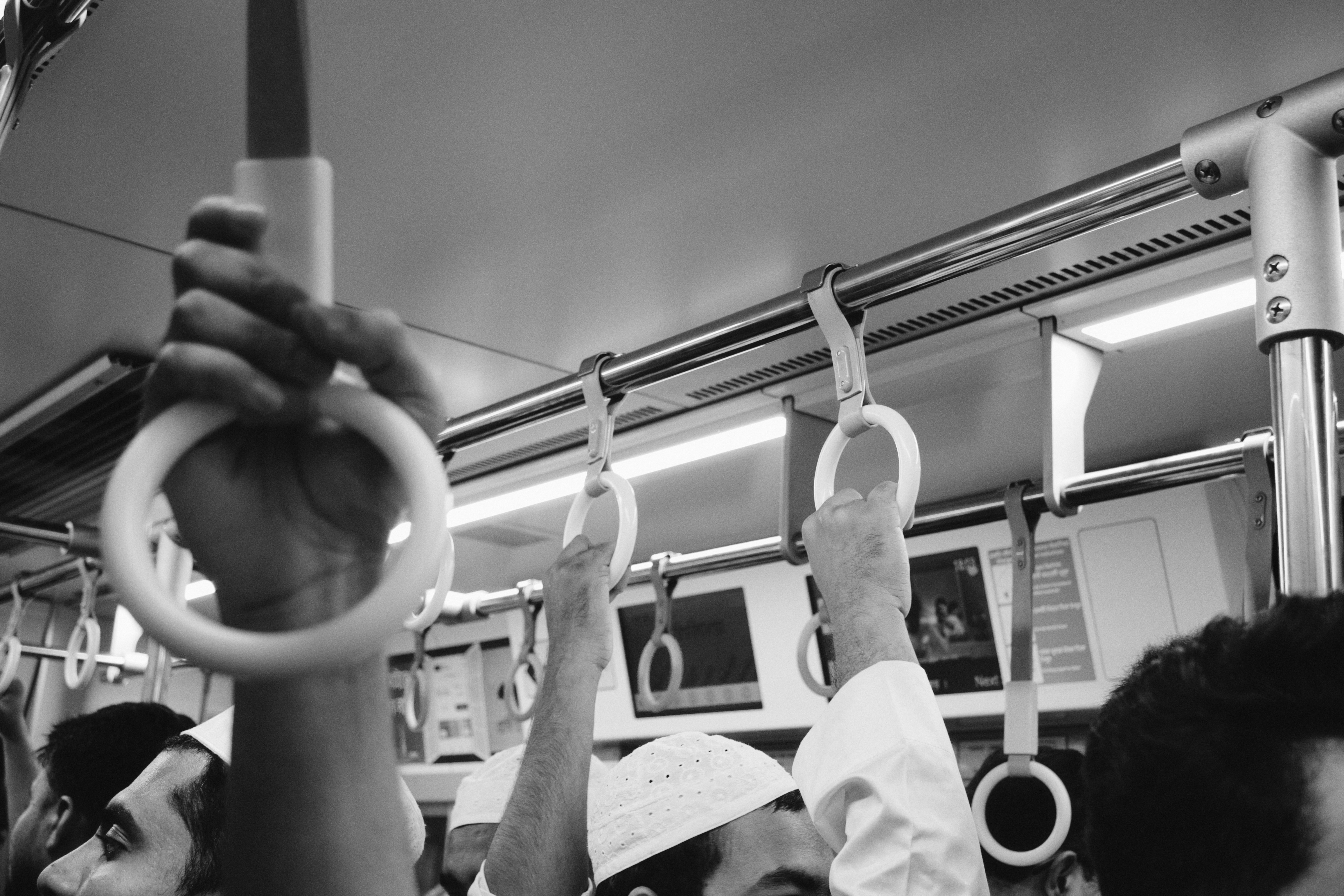 Hands grip the handrails on a crowded subway.