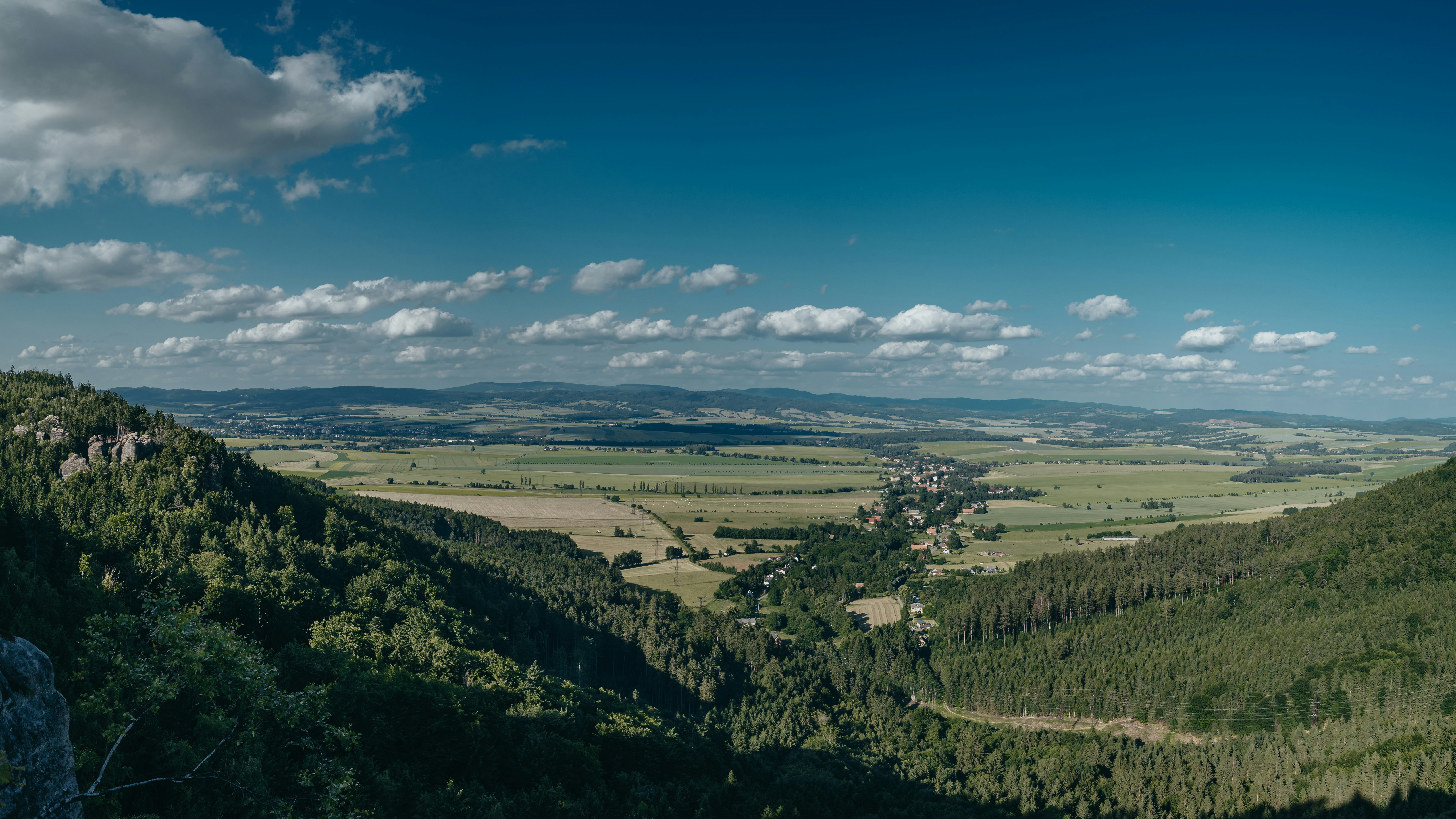 Vast green valley stretches under a bright blue sky.