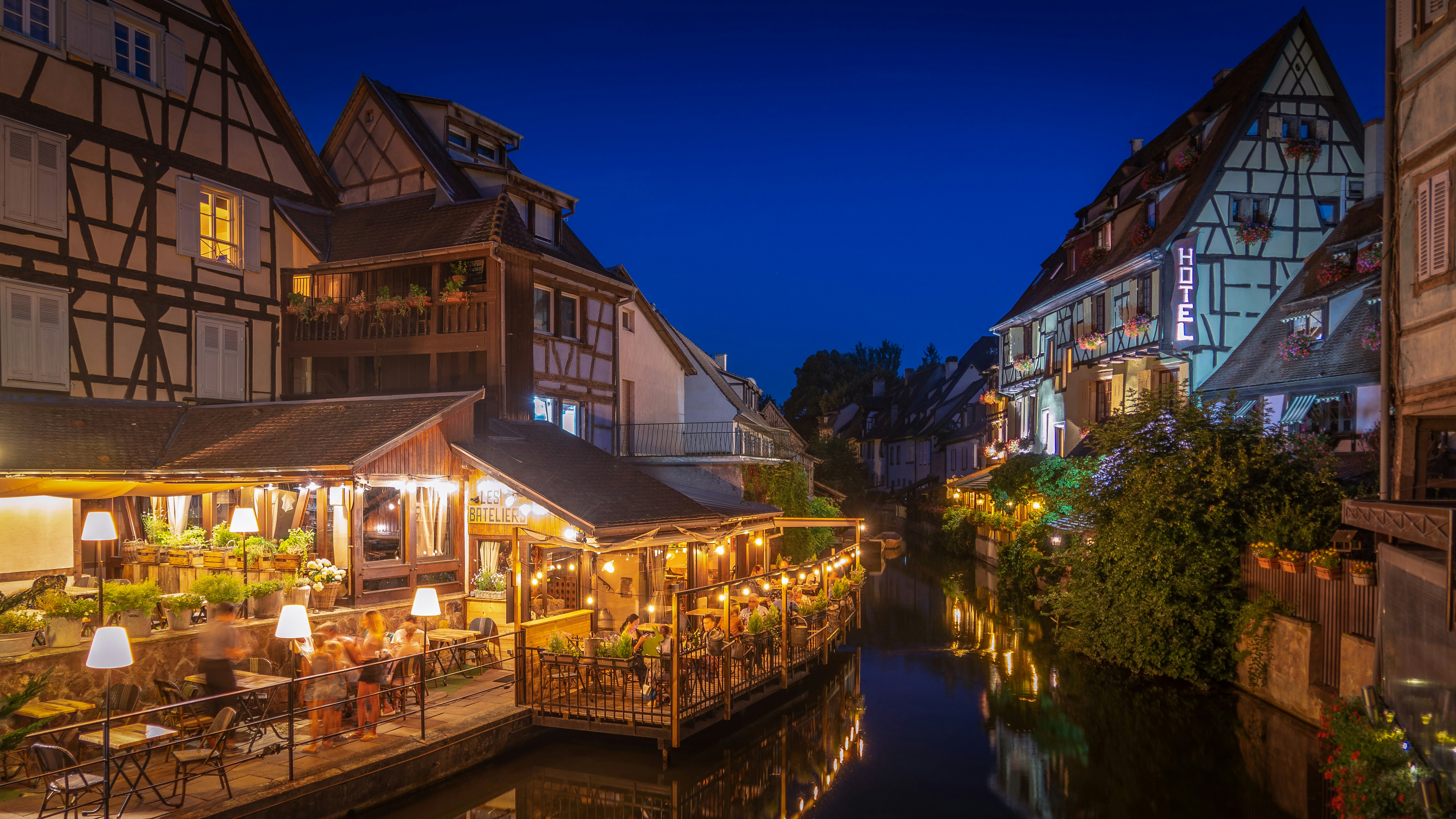 Colmar’s Little Venice shining bright at blue hour. | Luminous buildings line a canal at night.