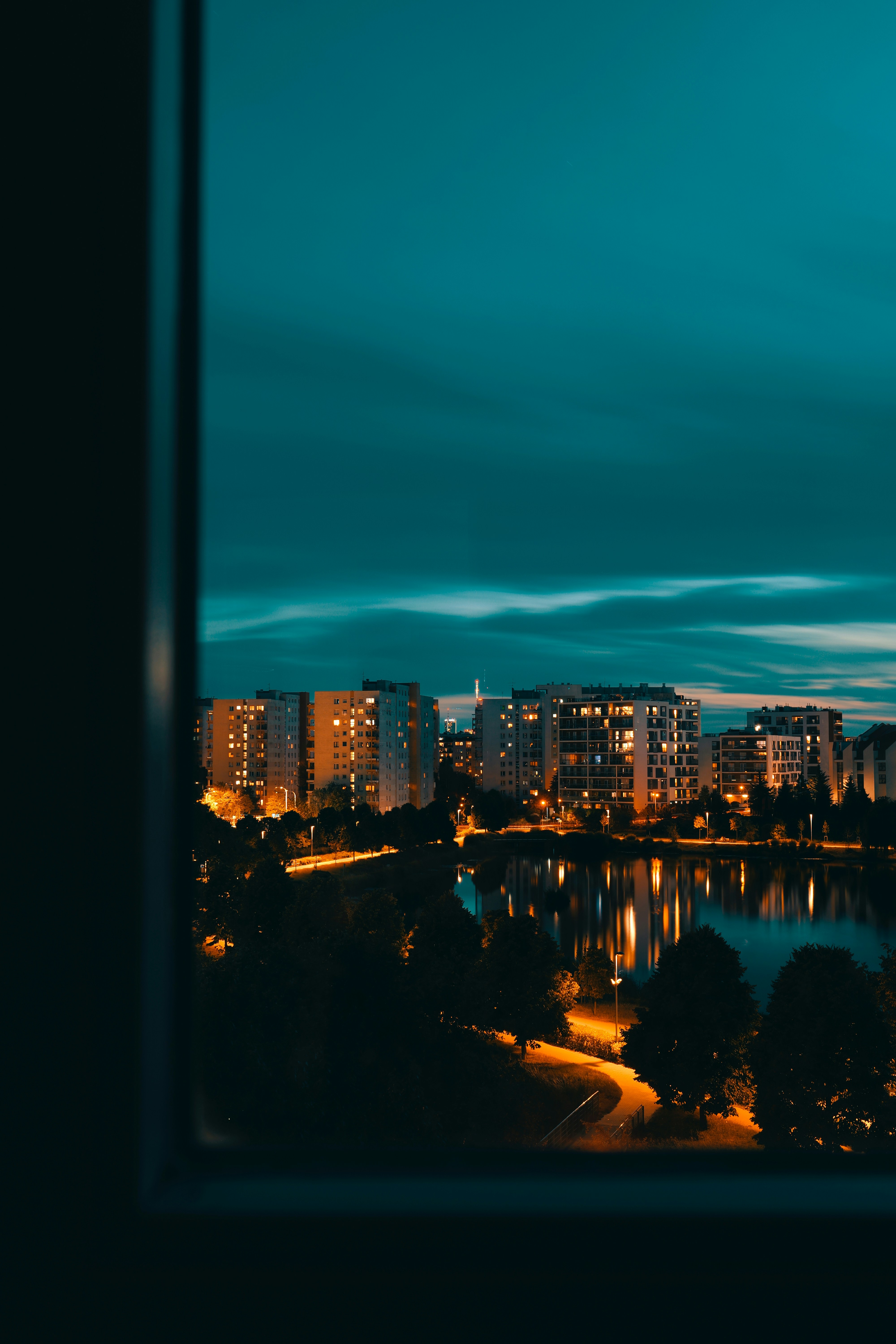 City lights shine over a lake at dusk.
