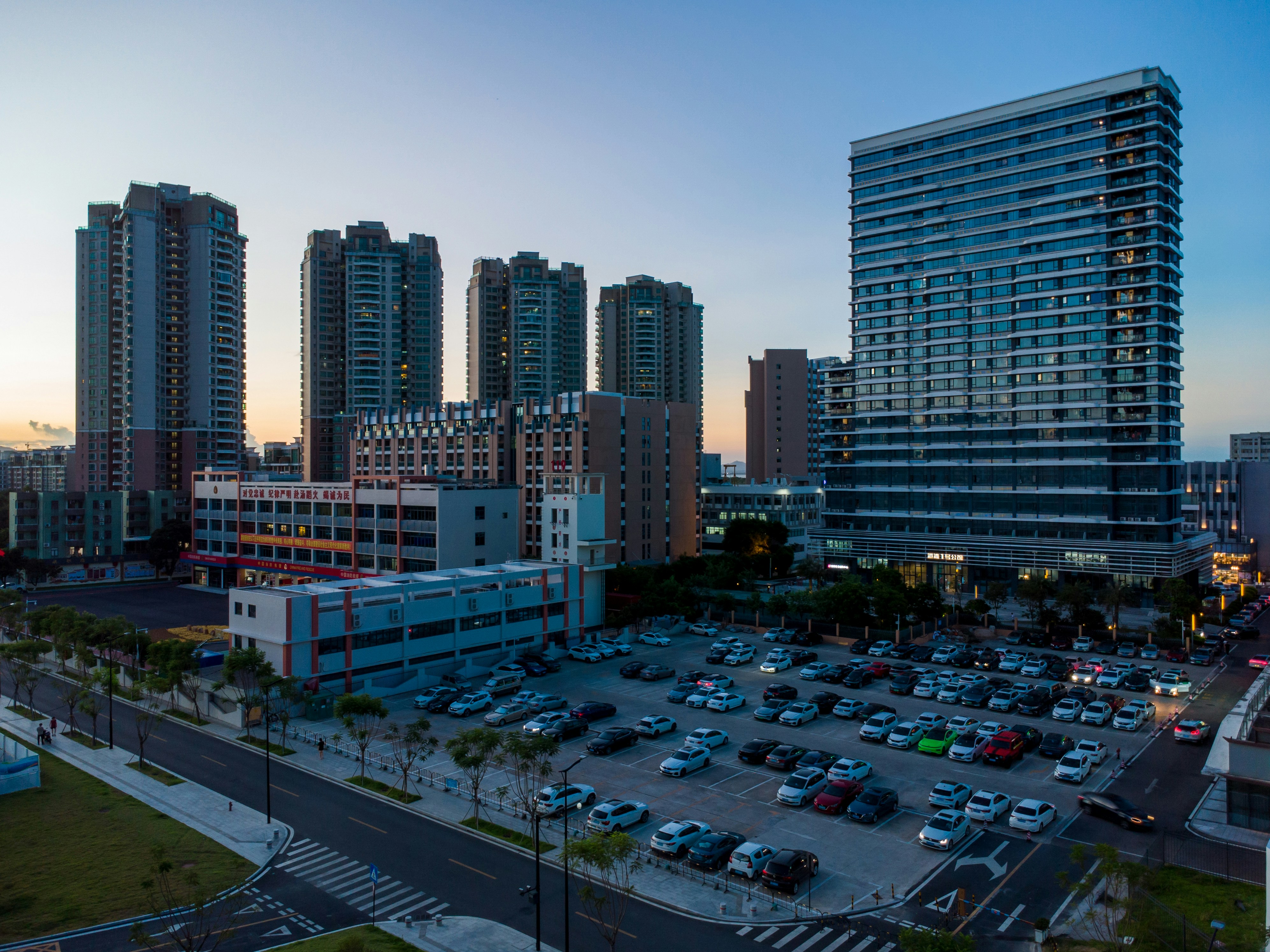 High-rise buildings and a parking lot at dusk. photo – Free Car Image ...