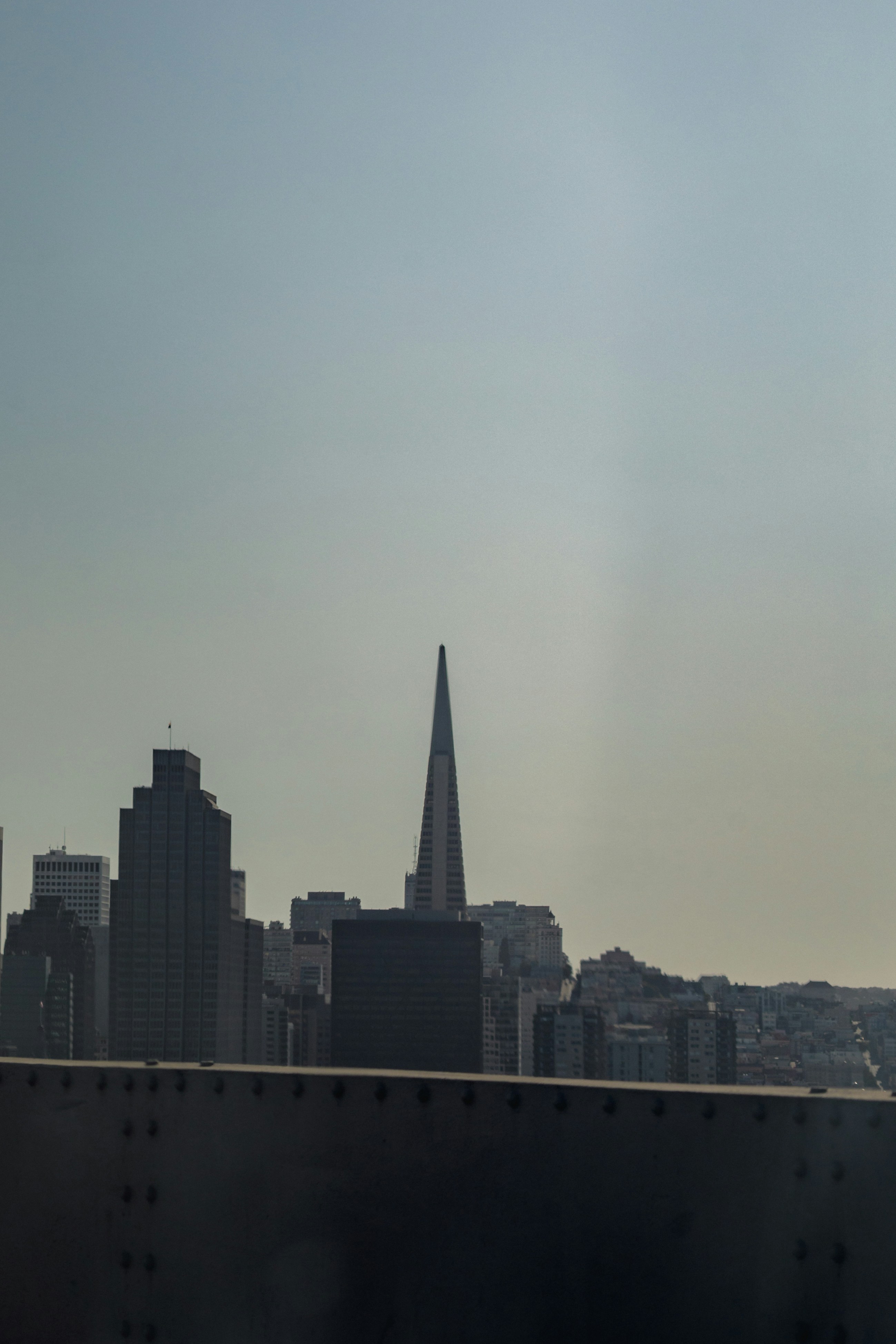 Silhouette of San Francisco's skyline featuring the distinctive spire of the Transamerica Pyramid against a hazy sky.