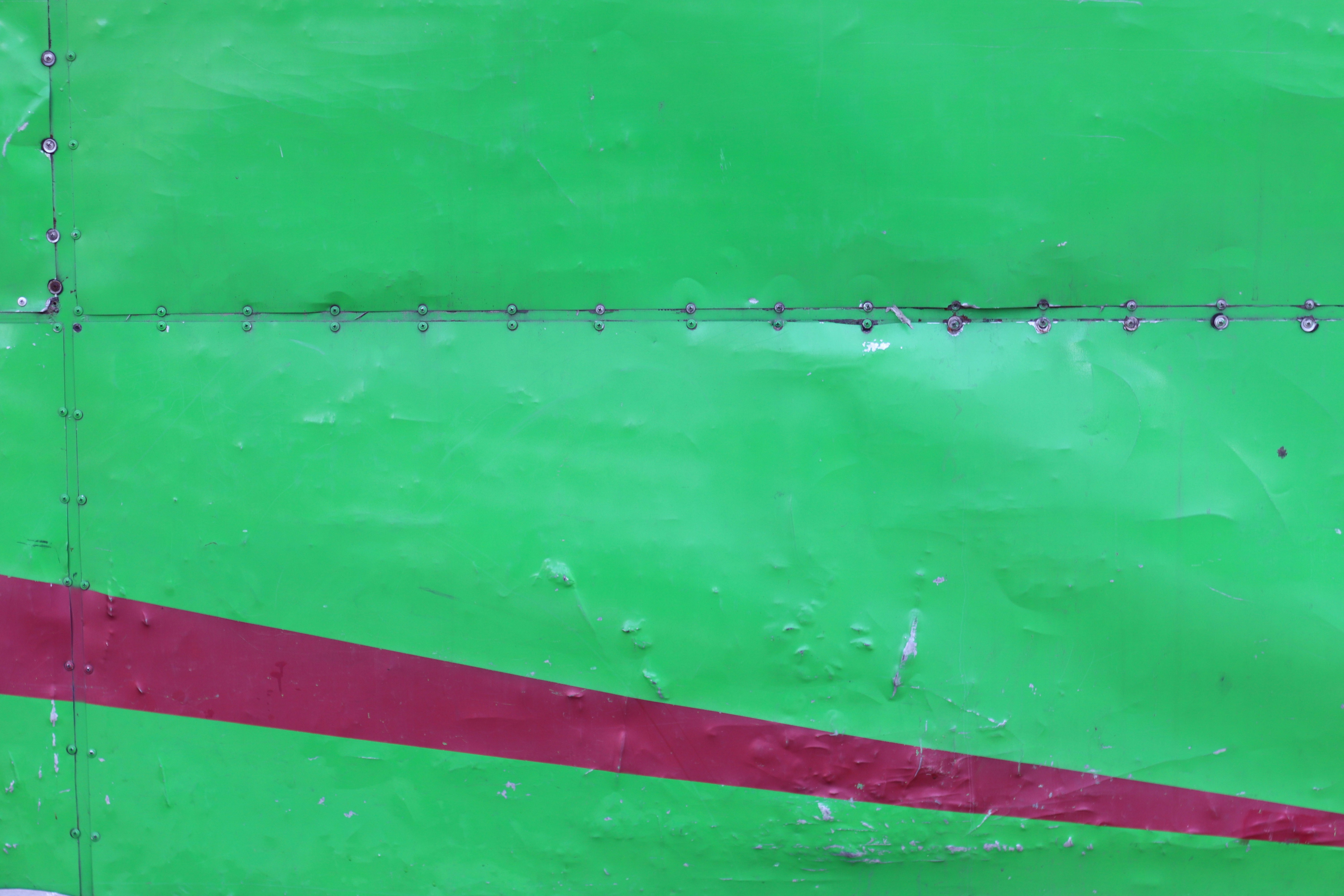 Crimson Diagonal Across Lime-Green Metal Panels