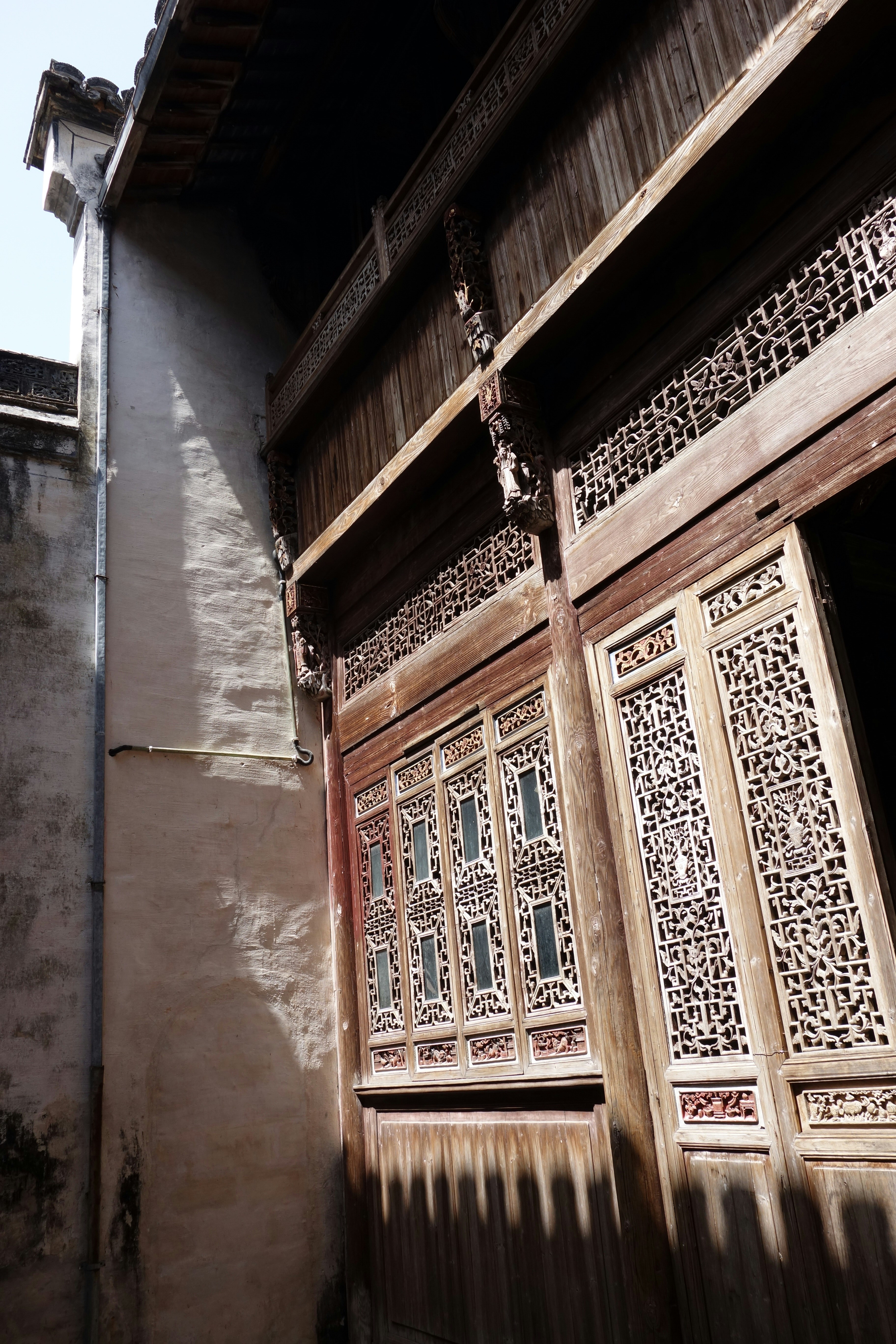 Elaborate wooden façade showcasing intricate carvings and traditional architecture, illuminated by soft sunlight.