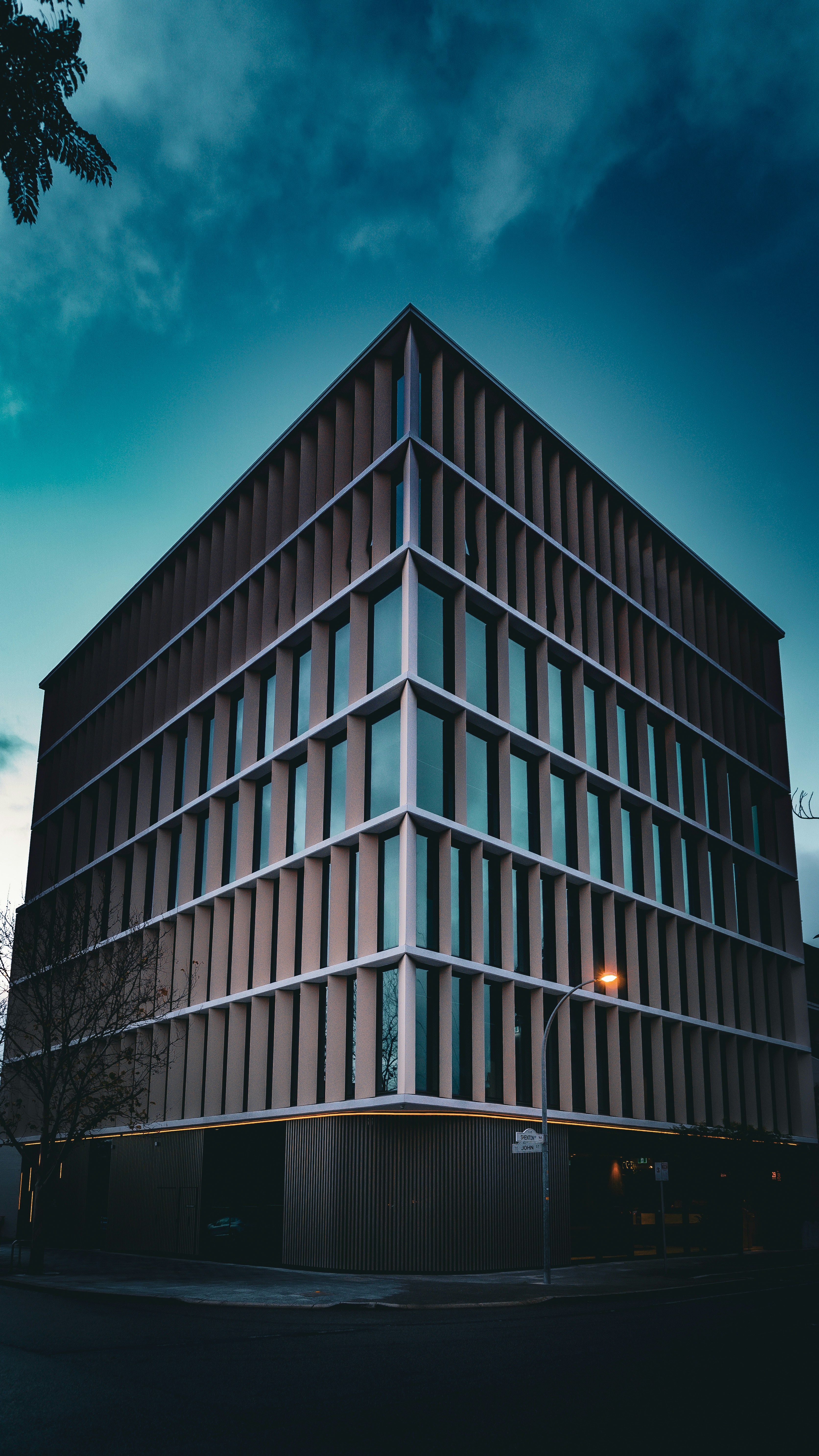 Modern building corner under a dramatic, cloudy sky.