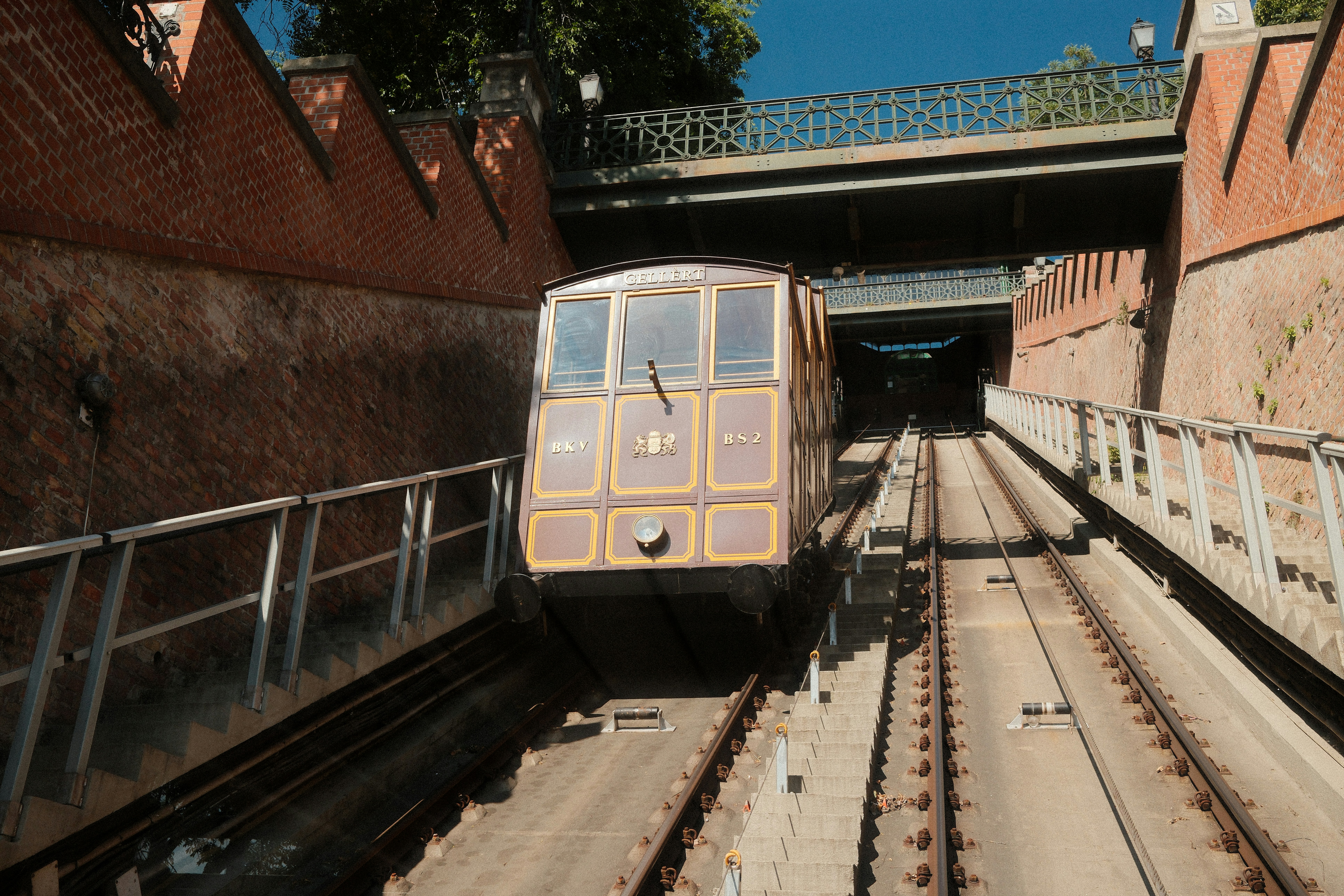 Heritage Tram Through a Brick Canyon Beneath a Sunlit Overpass