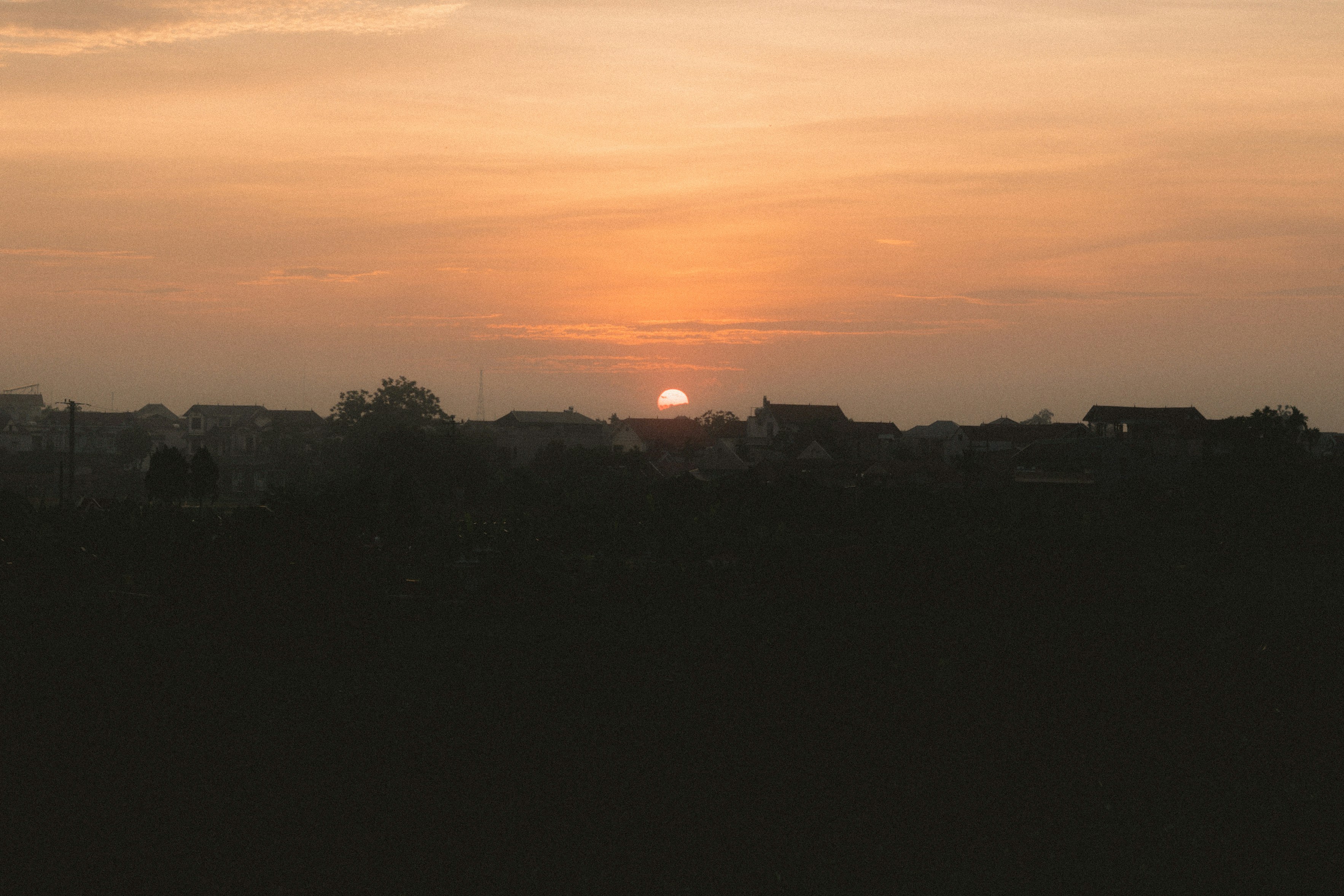 The sun sets over the horizon with an orange hue.